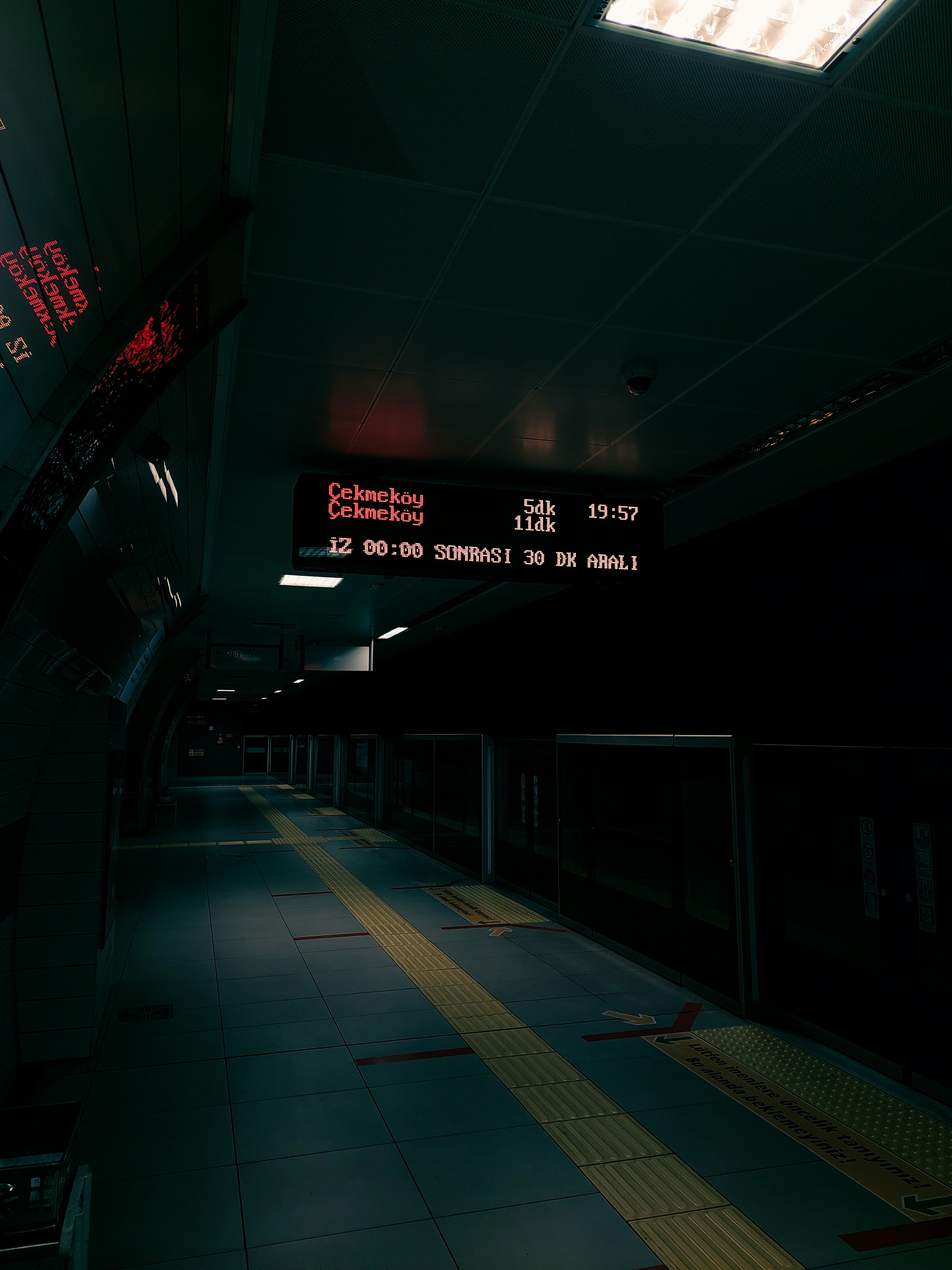 Digital timetable displaying train schedule at a subway station, with ambient lighting creating a moody atmosphere.