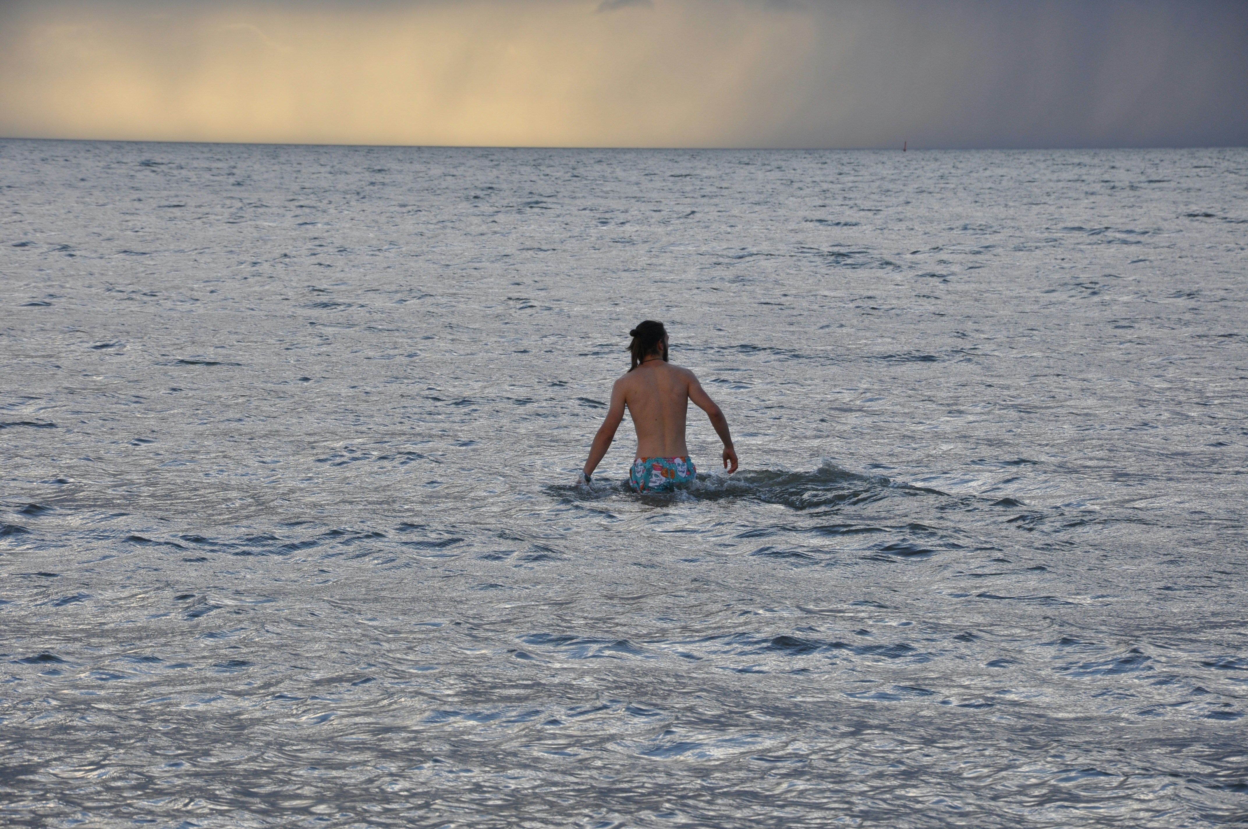  solitary swimmer ascending toward the horizon at a calm sea