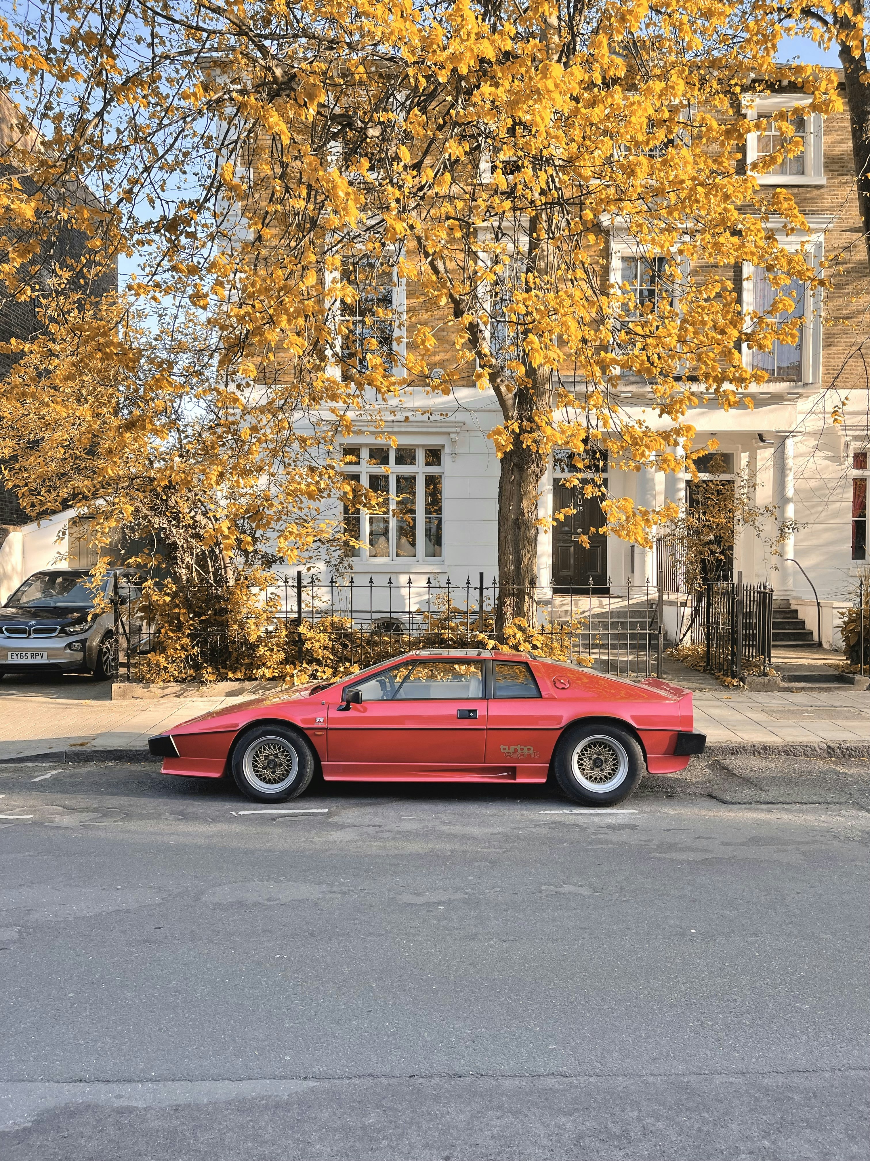 Red 80s sports coupe on a tree-framed autumn street
