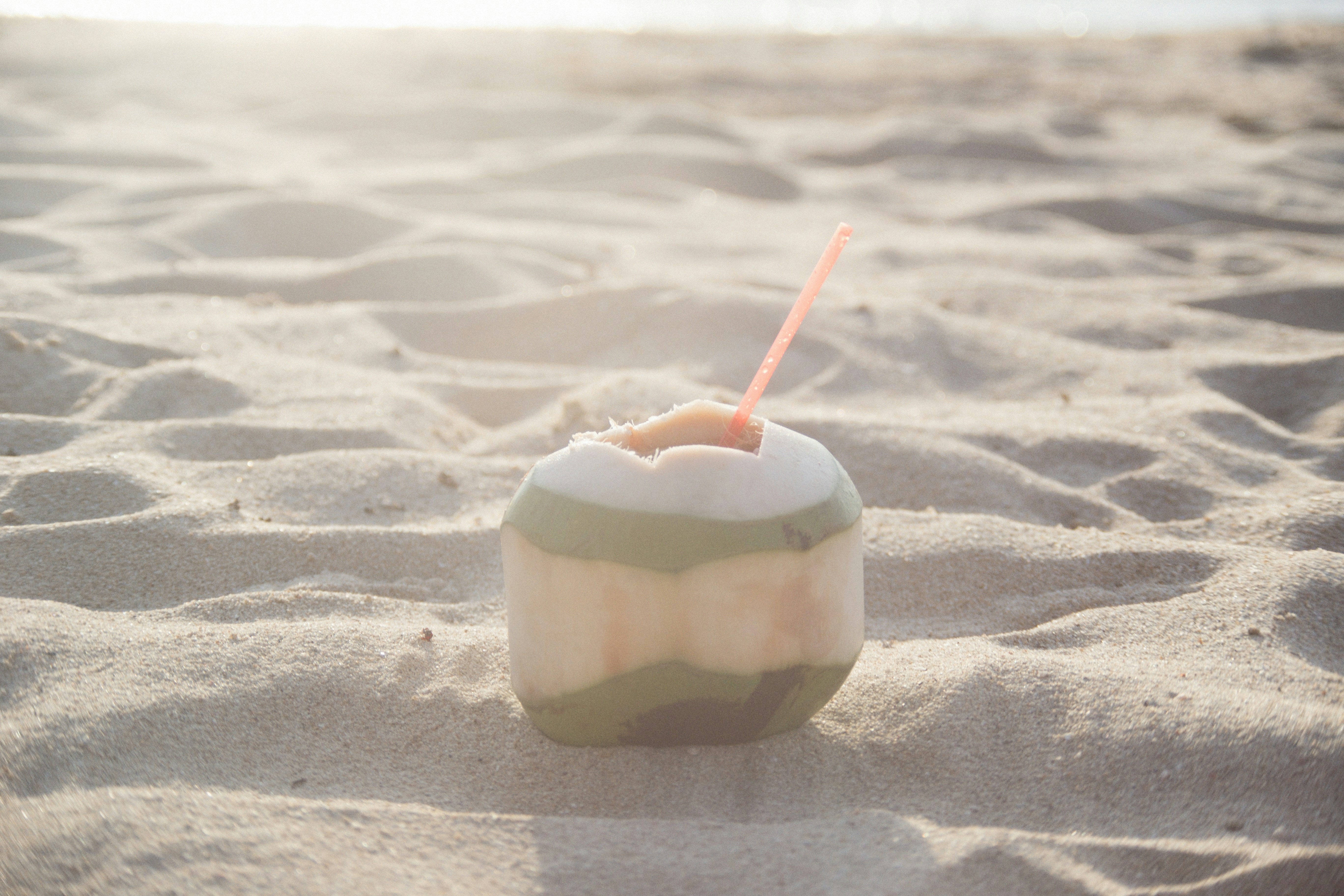 Sun-warmed Coconut with a Pink Straw on a Quiet Beach