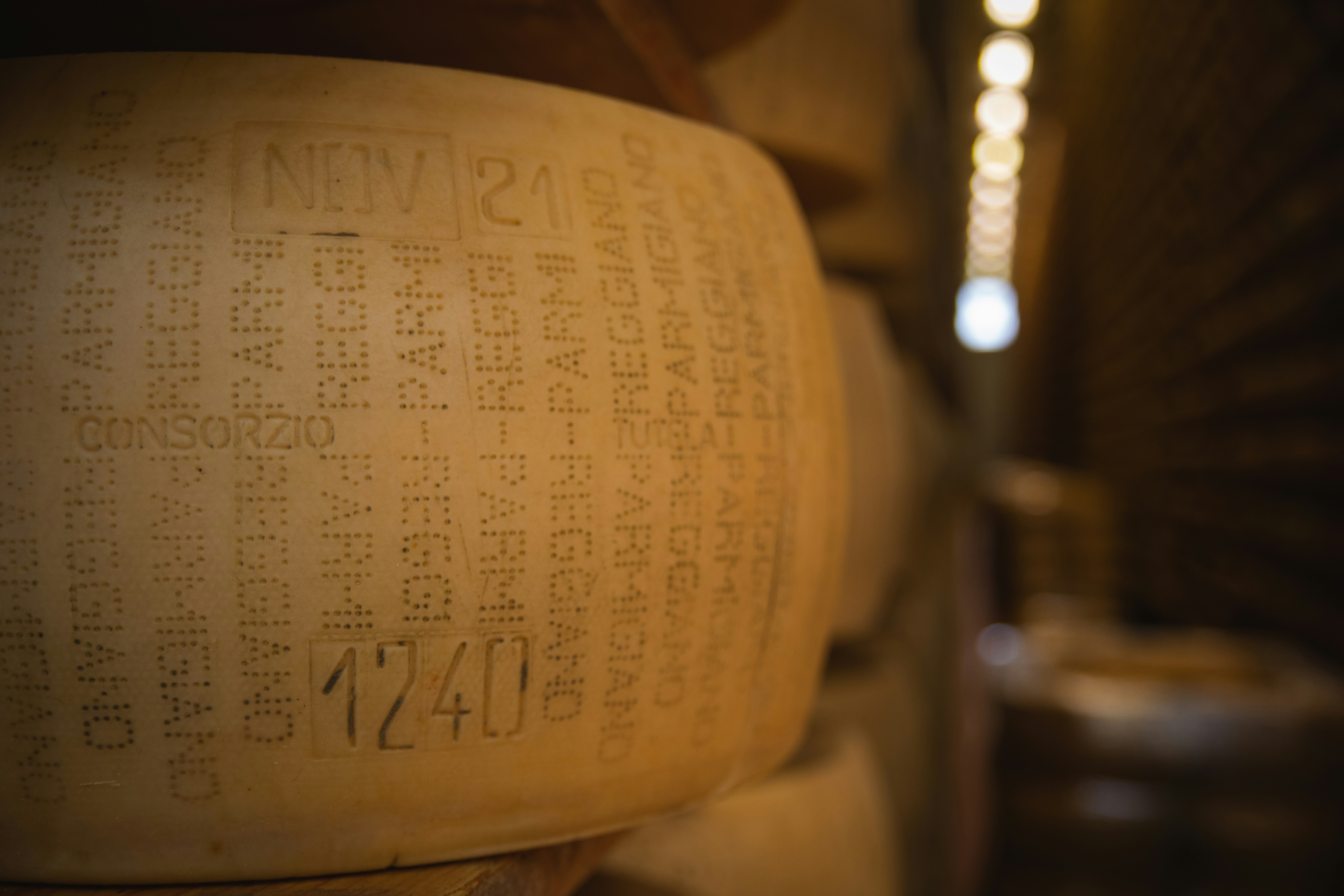 Rows of Parmigiano-Reggiano wheels aging in a dimly lit cellar.