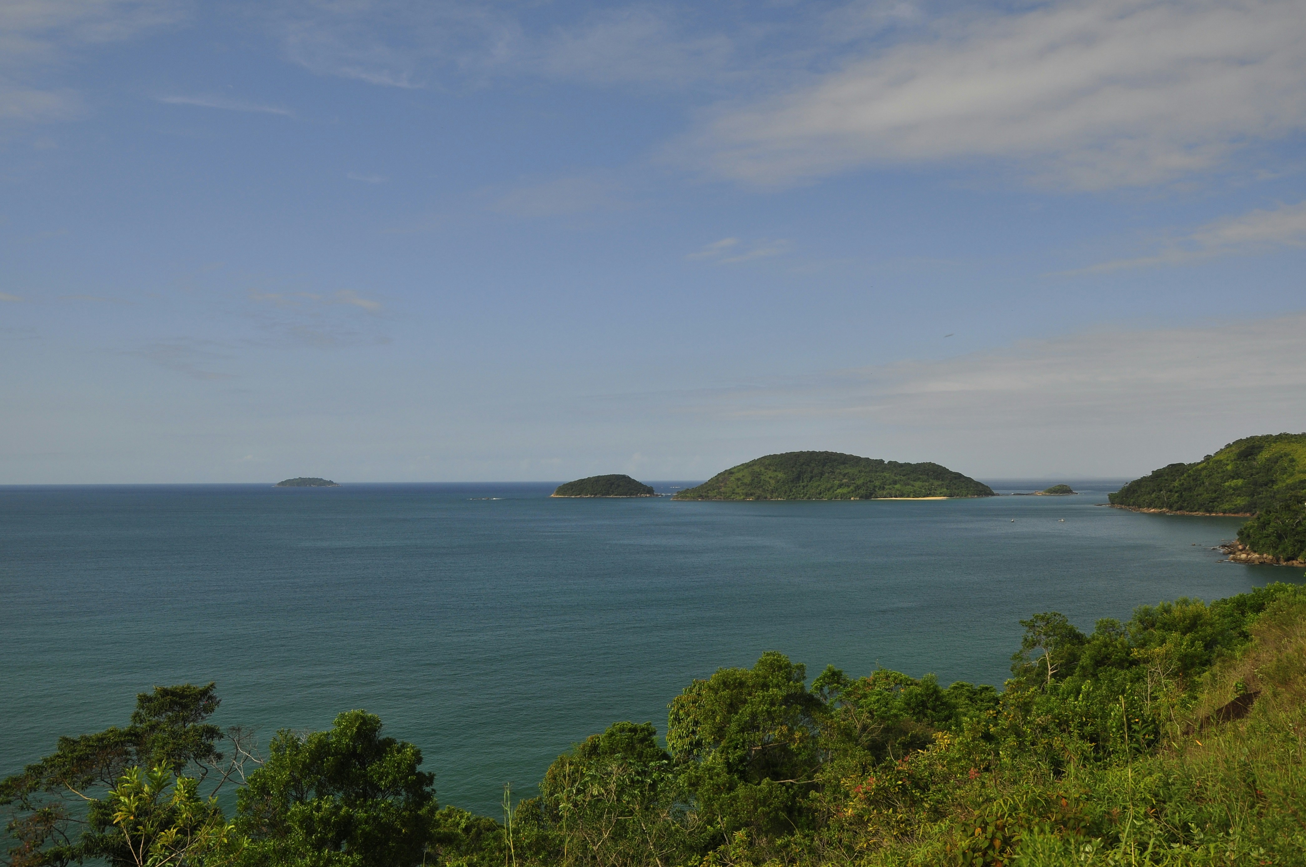 Blue ocean stretching towards distant green islands under a clear sky.