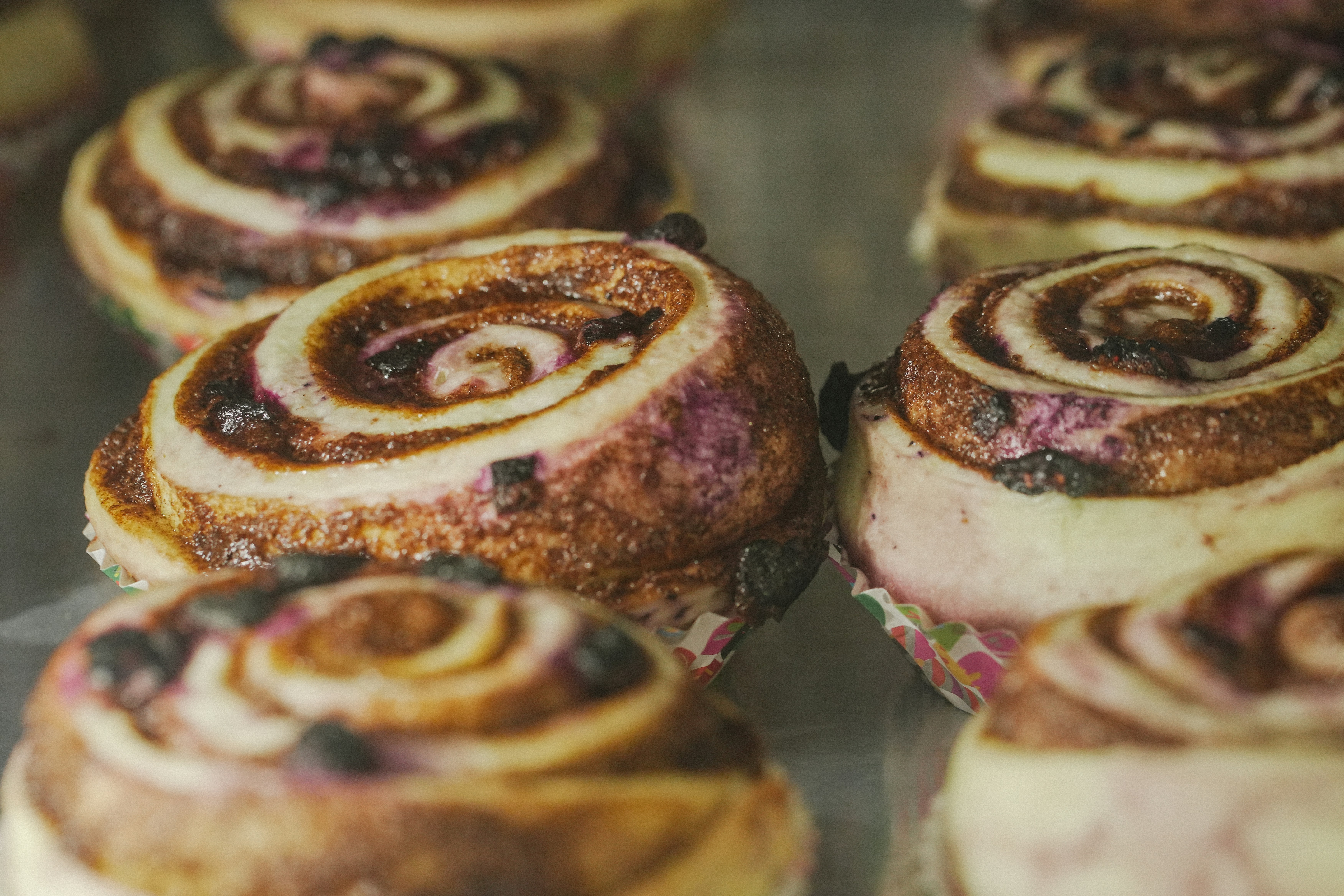 Freshly baked cinnamon rolls with a rich, golden-brown crust dotted with berries.