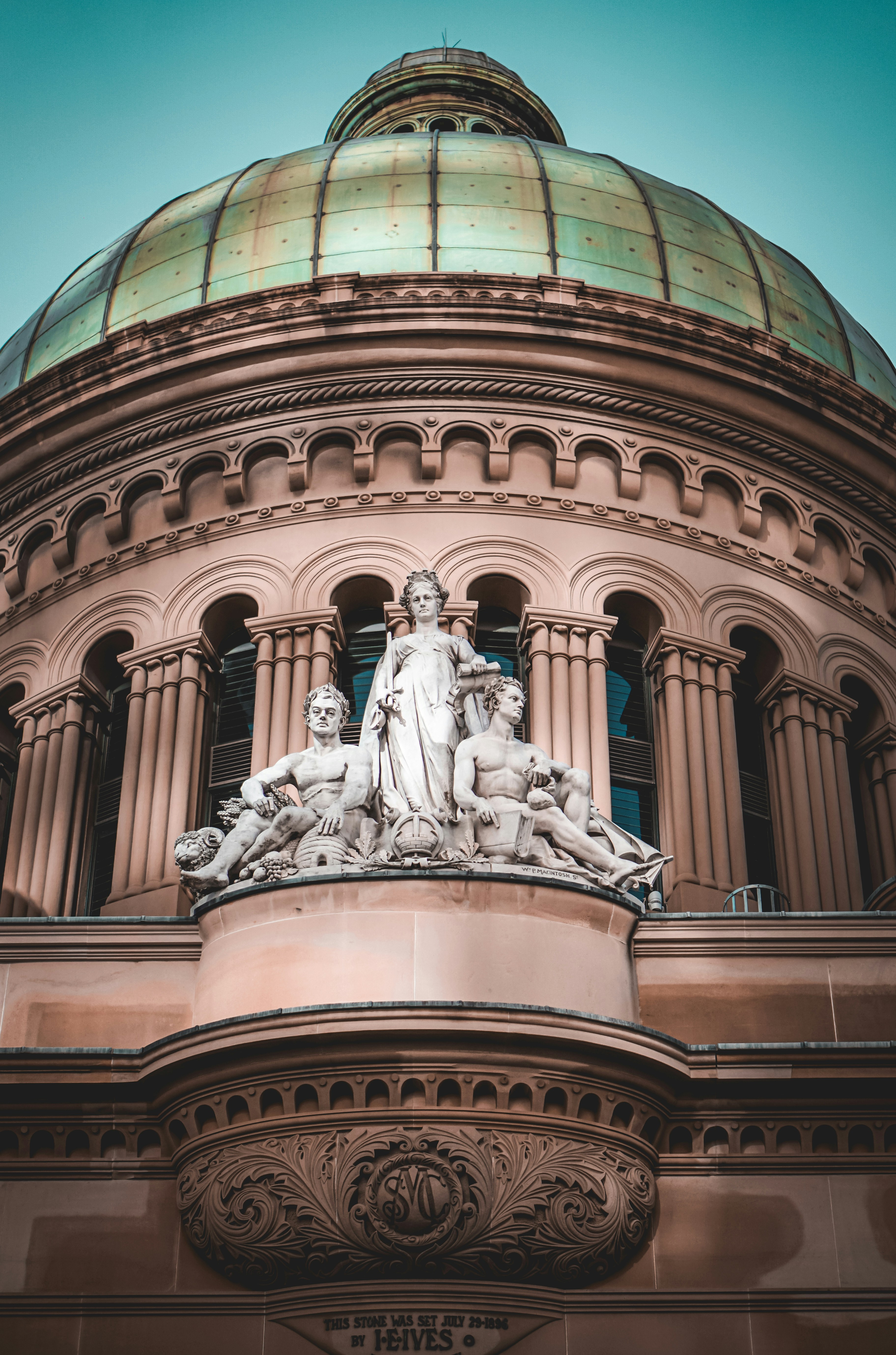 Elegant architectural sculpture featuring figures representing art and knowledge, set against a grand dome backdrop.