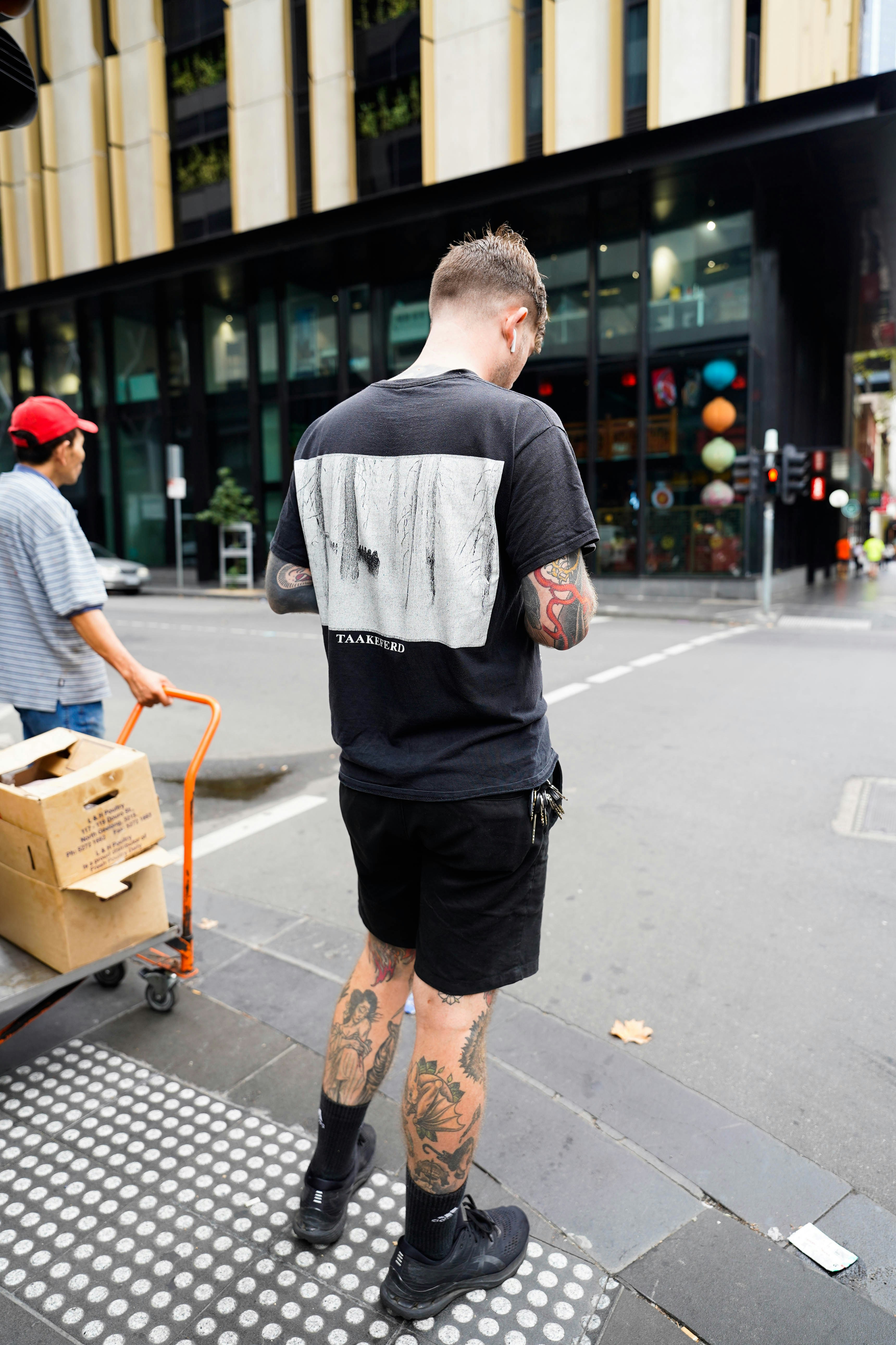 Back View on a City Street: Tattooed Pedestrian by a Glass-Front Storefront