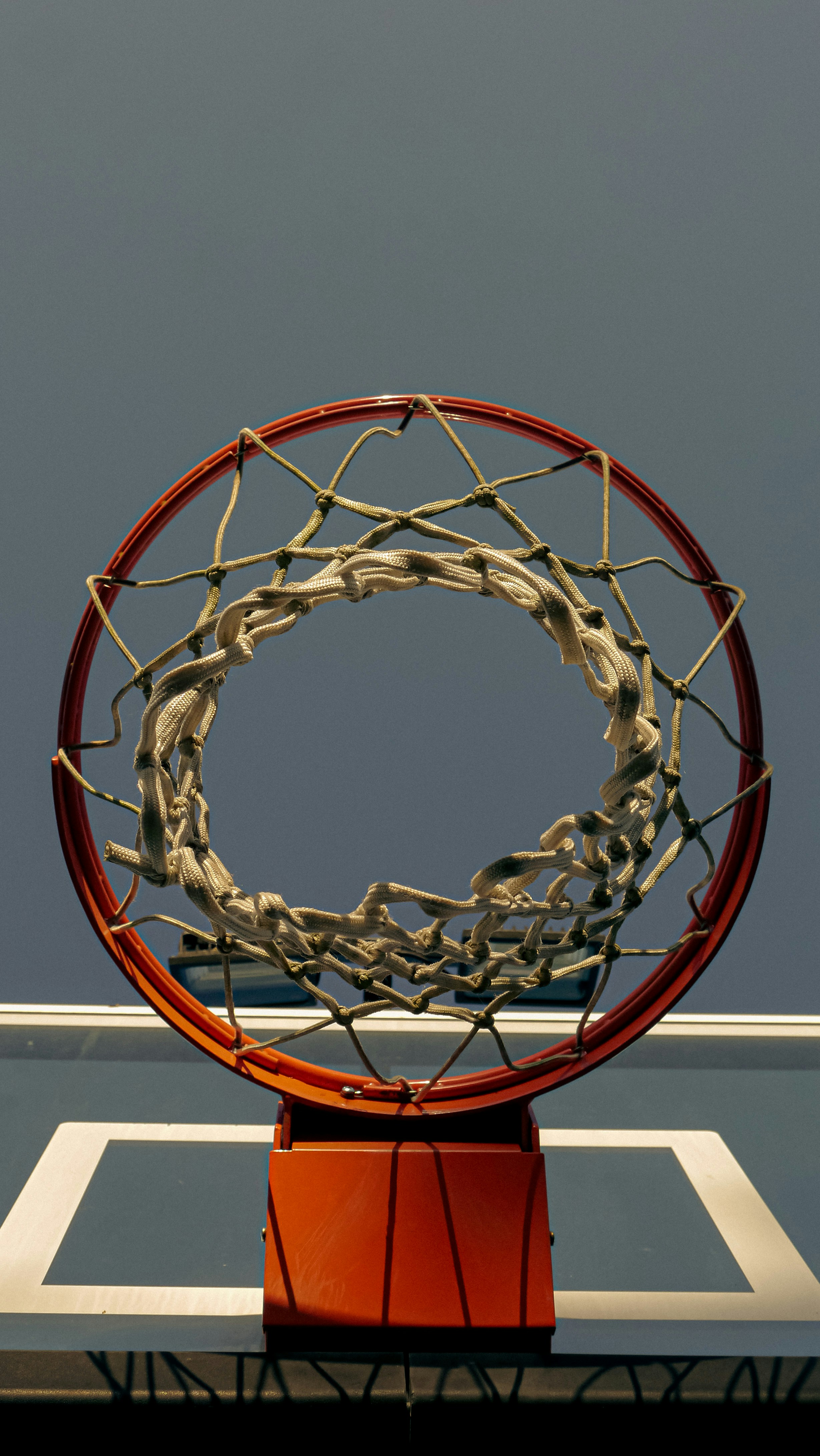 Basketball hoop against a smooth gradient background, showcasing the intricate netting and vibrant colors. 