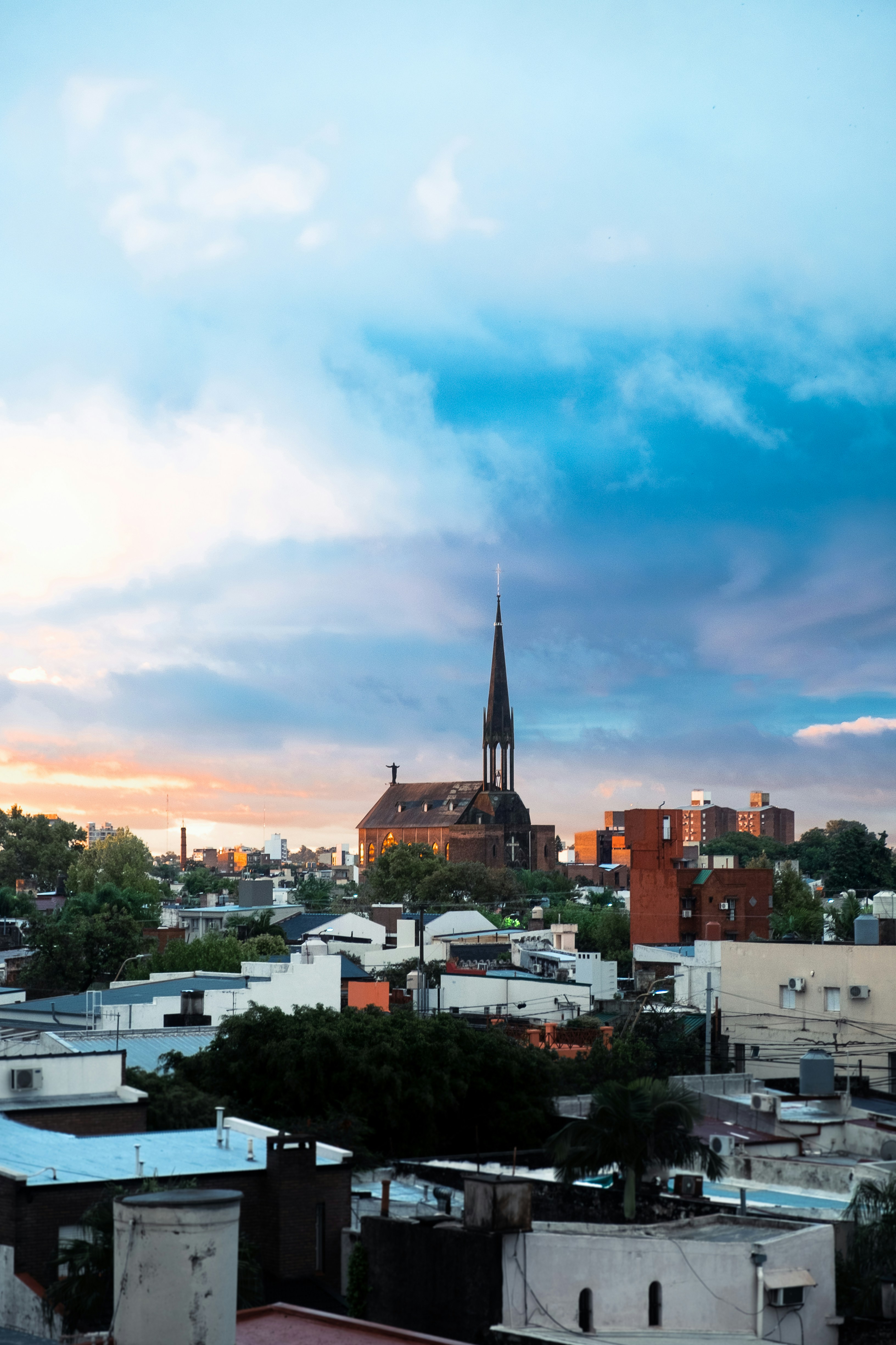 Historic church spire rising above a patchwork of rooftops under a twilight sky.