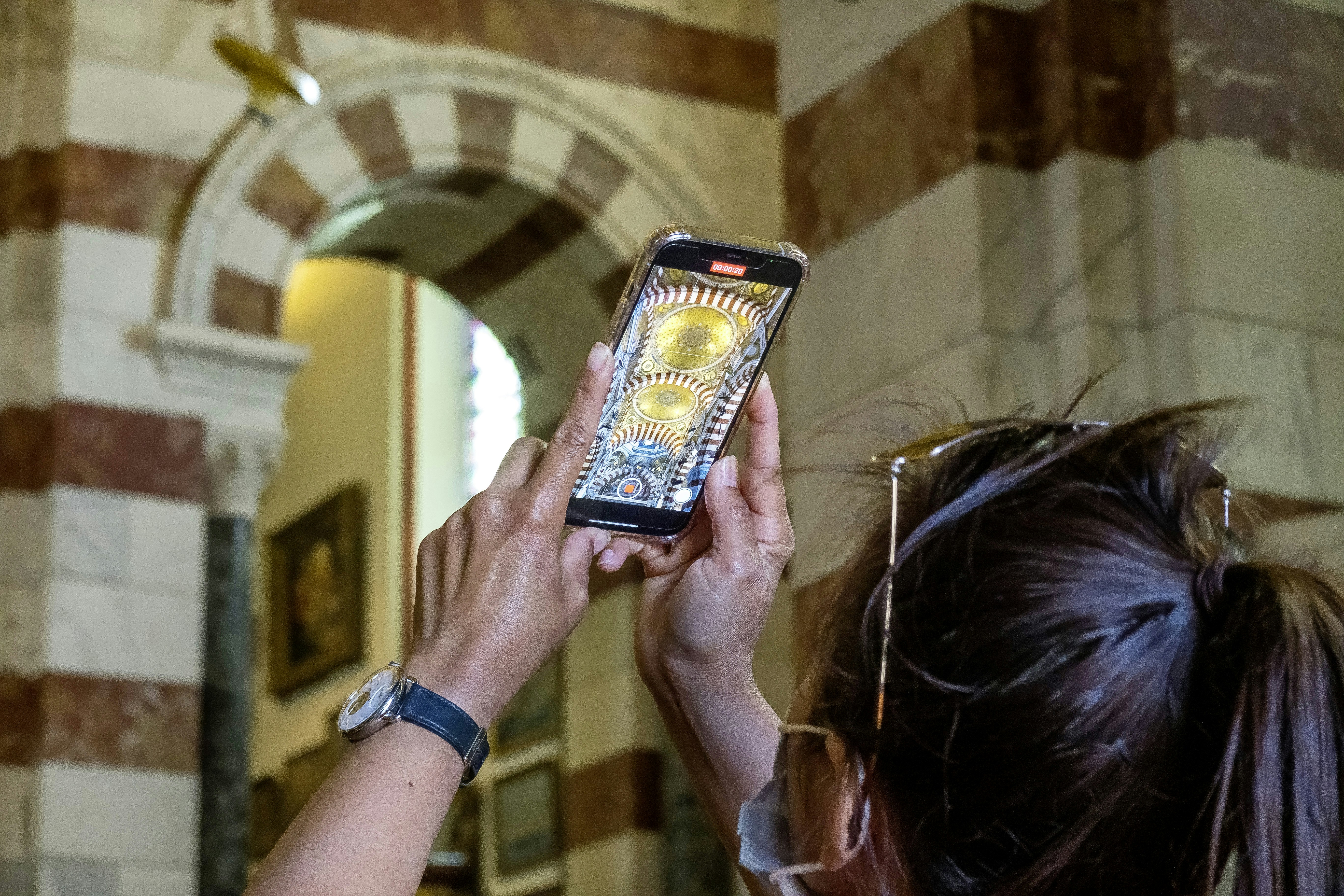 Phone-centered fresco: a viewer captures architectural detail via a handheld device