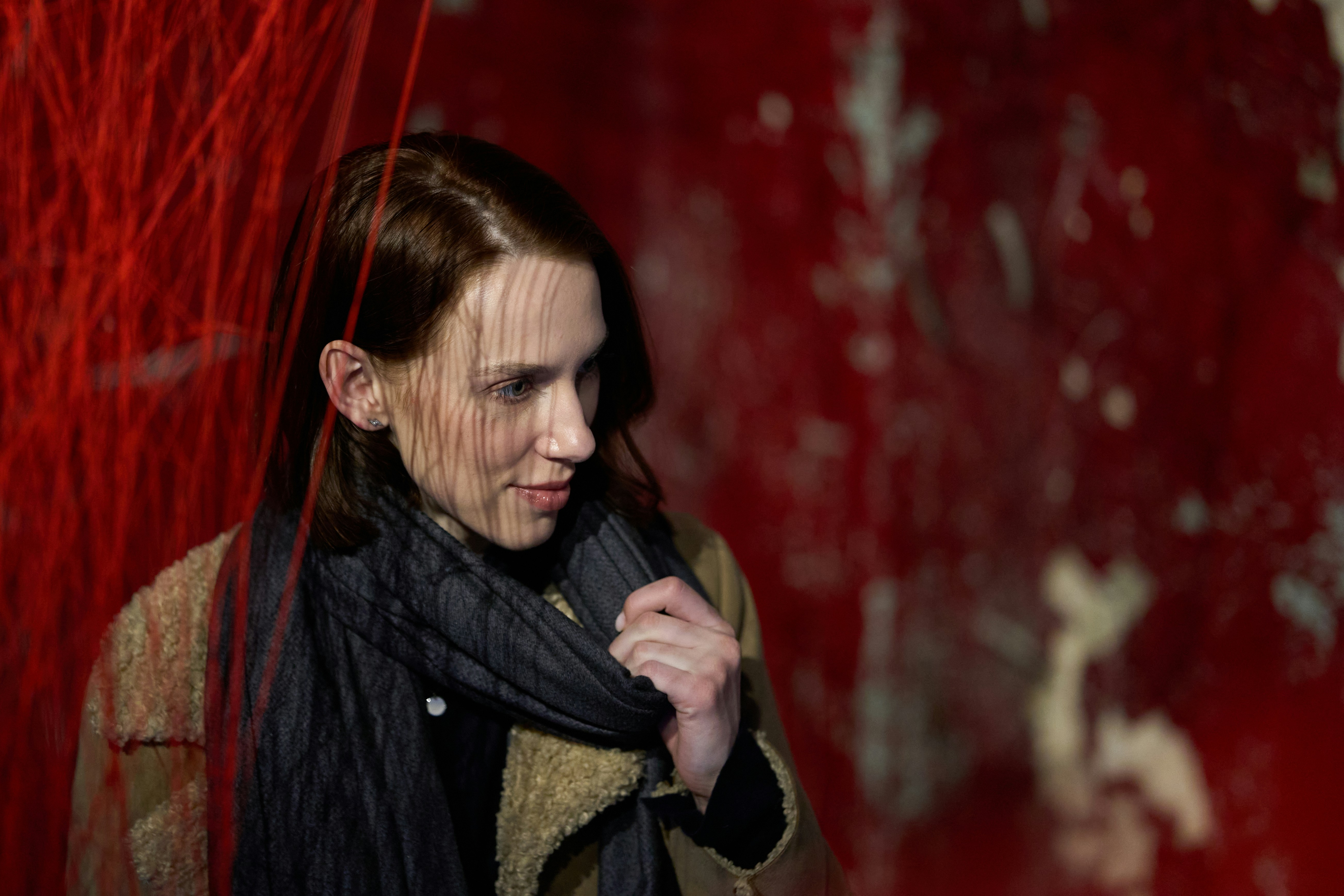 Velvet Red Portrait: Quiet Focus Amid Hanging Threads