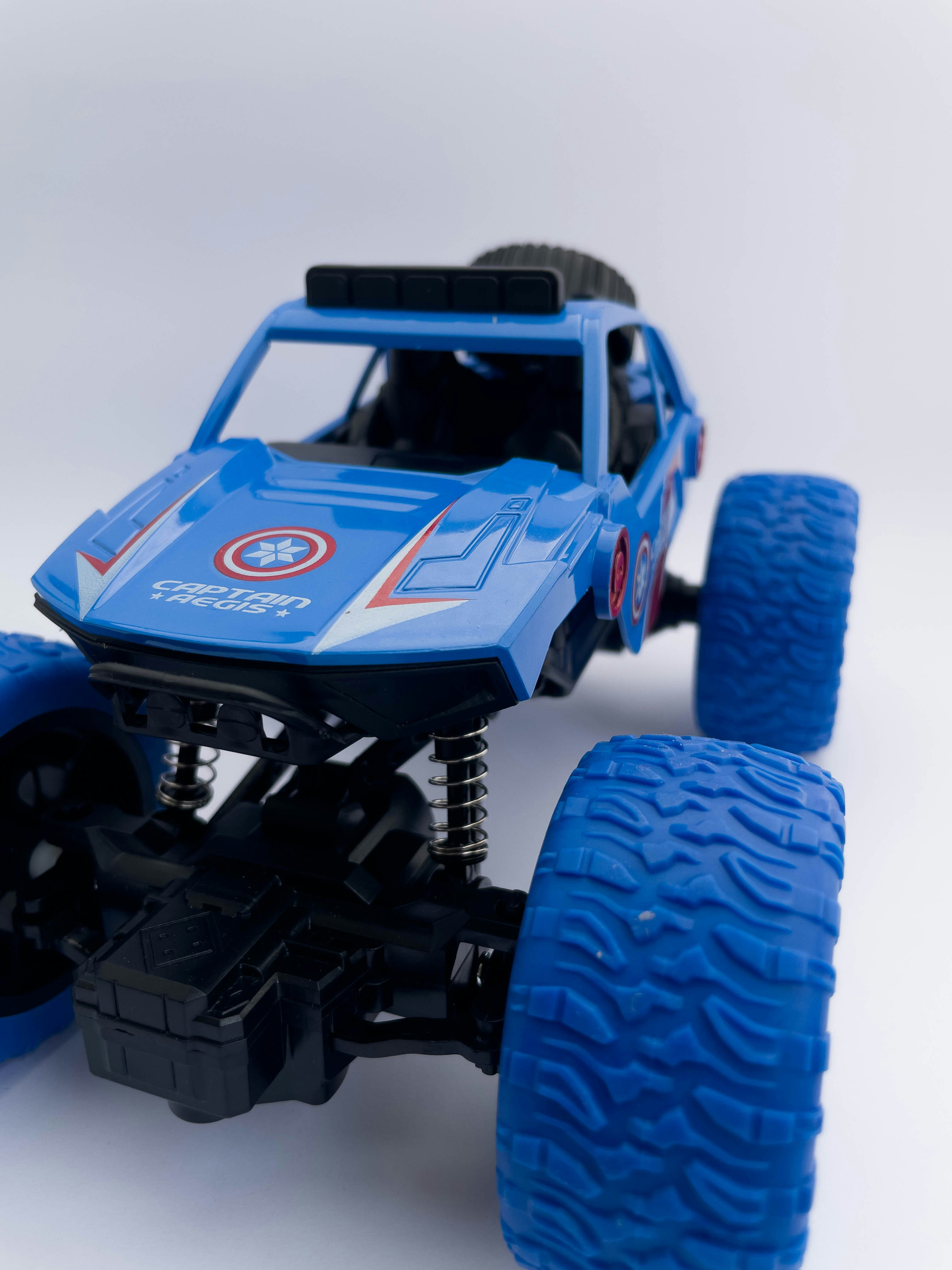 Blue toy monster truck designed with superhero motifs and oversized tires, showcasing a playful spirit. Captures the essence of adventure and fun.