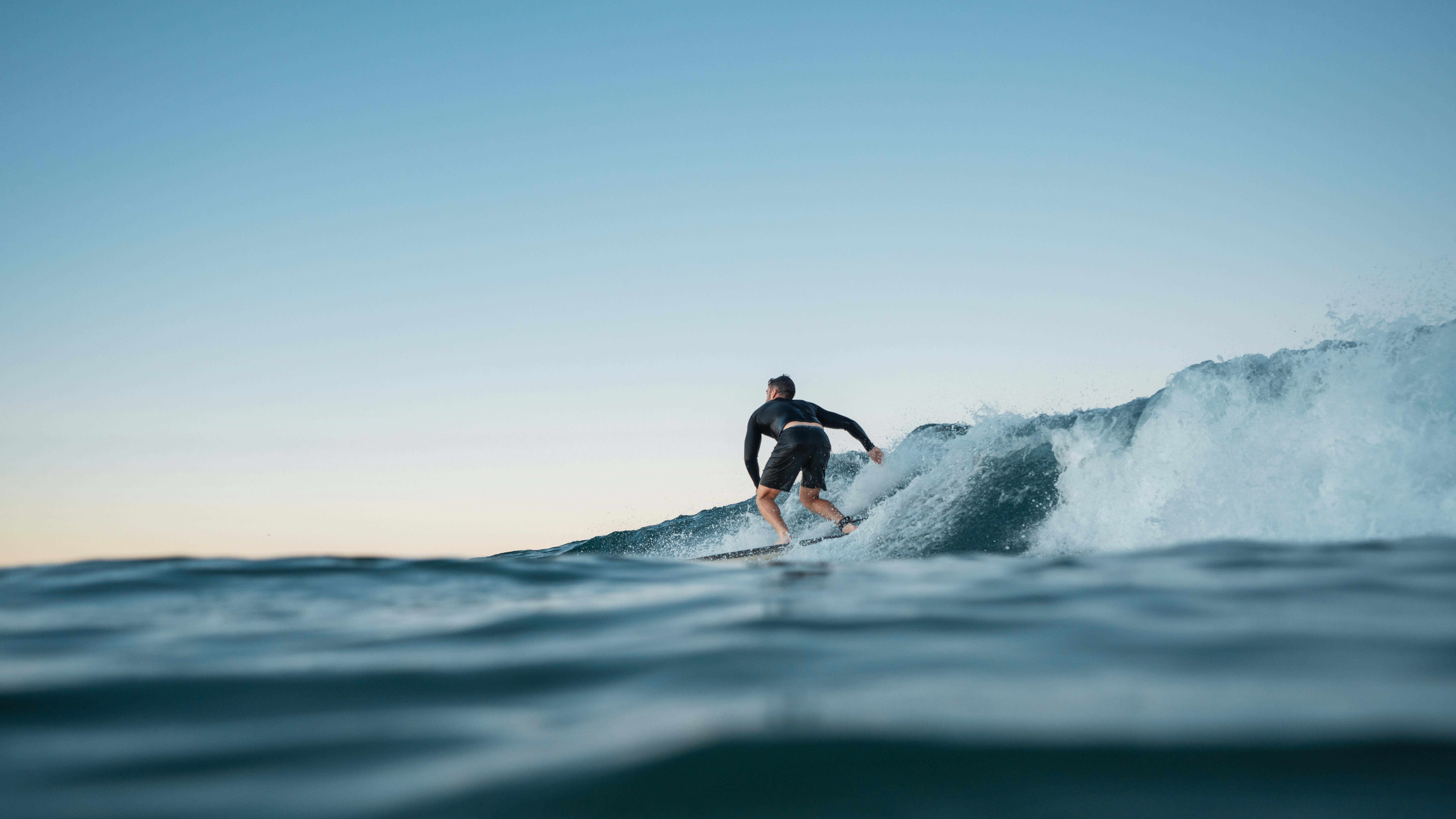 Un homme chevauchant une vague sur une planche de surf dans l’océan ...