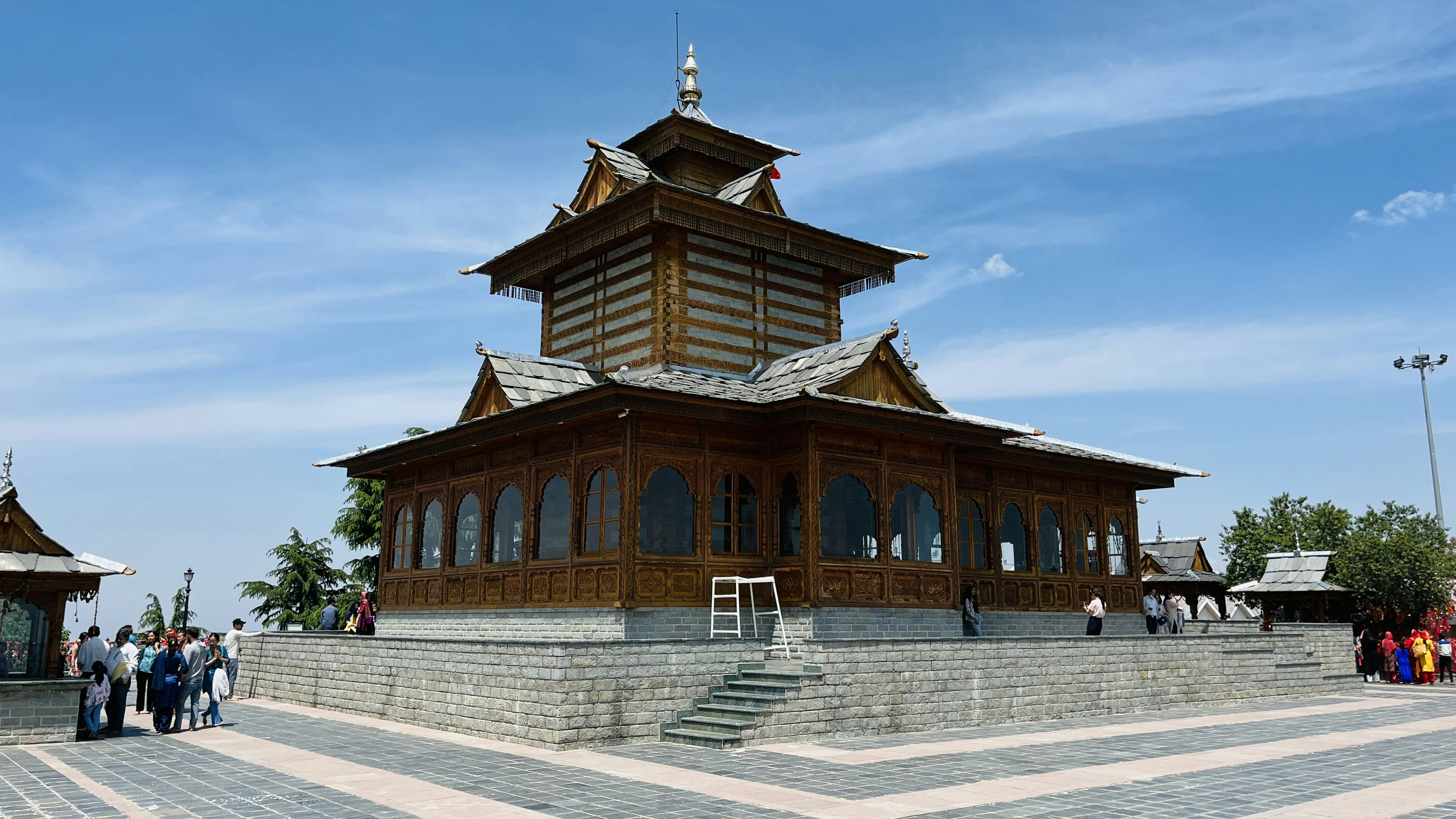 Intricate wooden architecture of a traditional structure surrounded by visitors, showcasing cultural significance and craftsmanship.