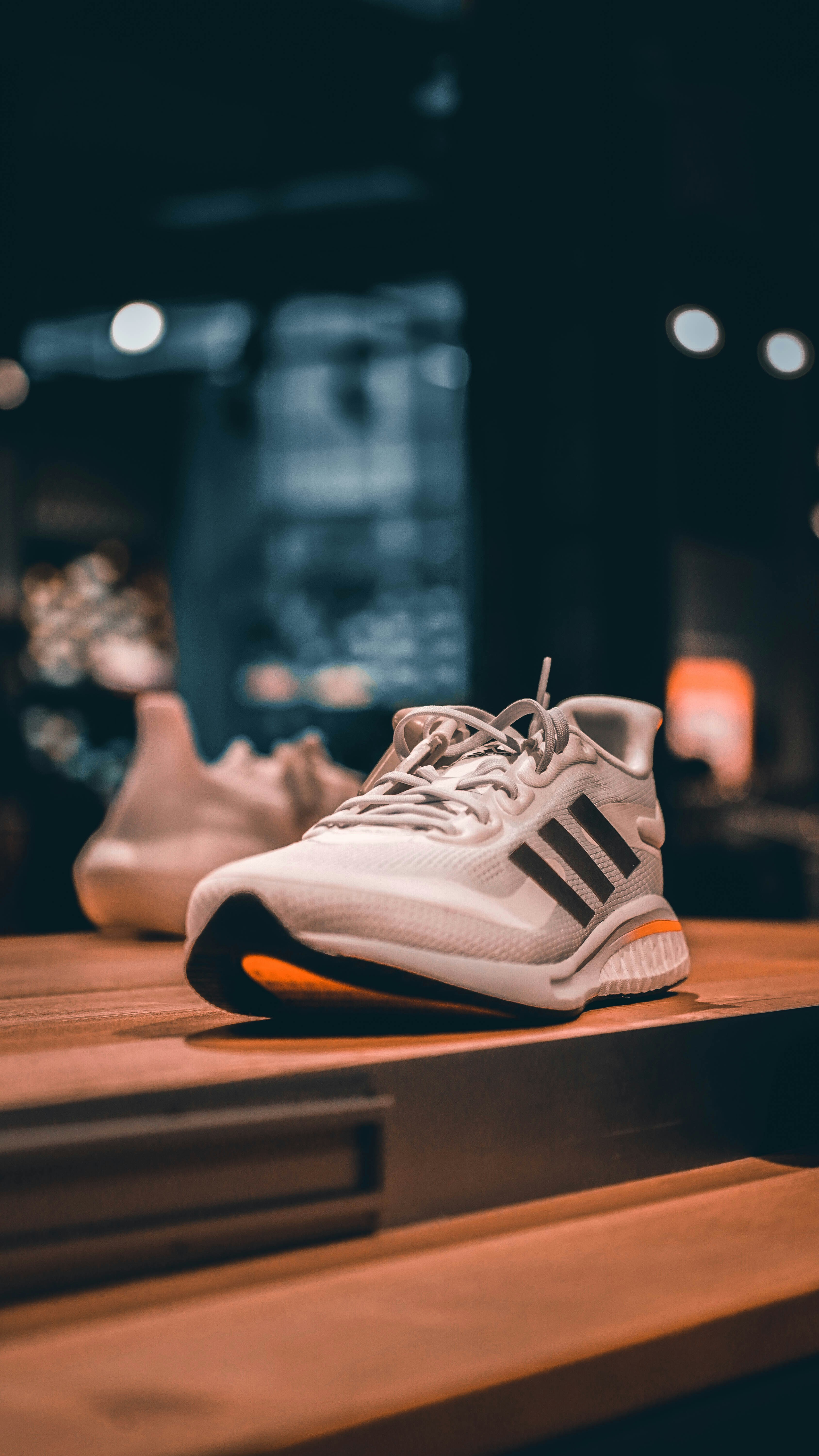 Spotlight on the Sole: White Adidas Running Shoe on a Wood Display