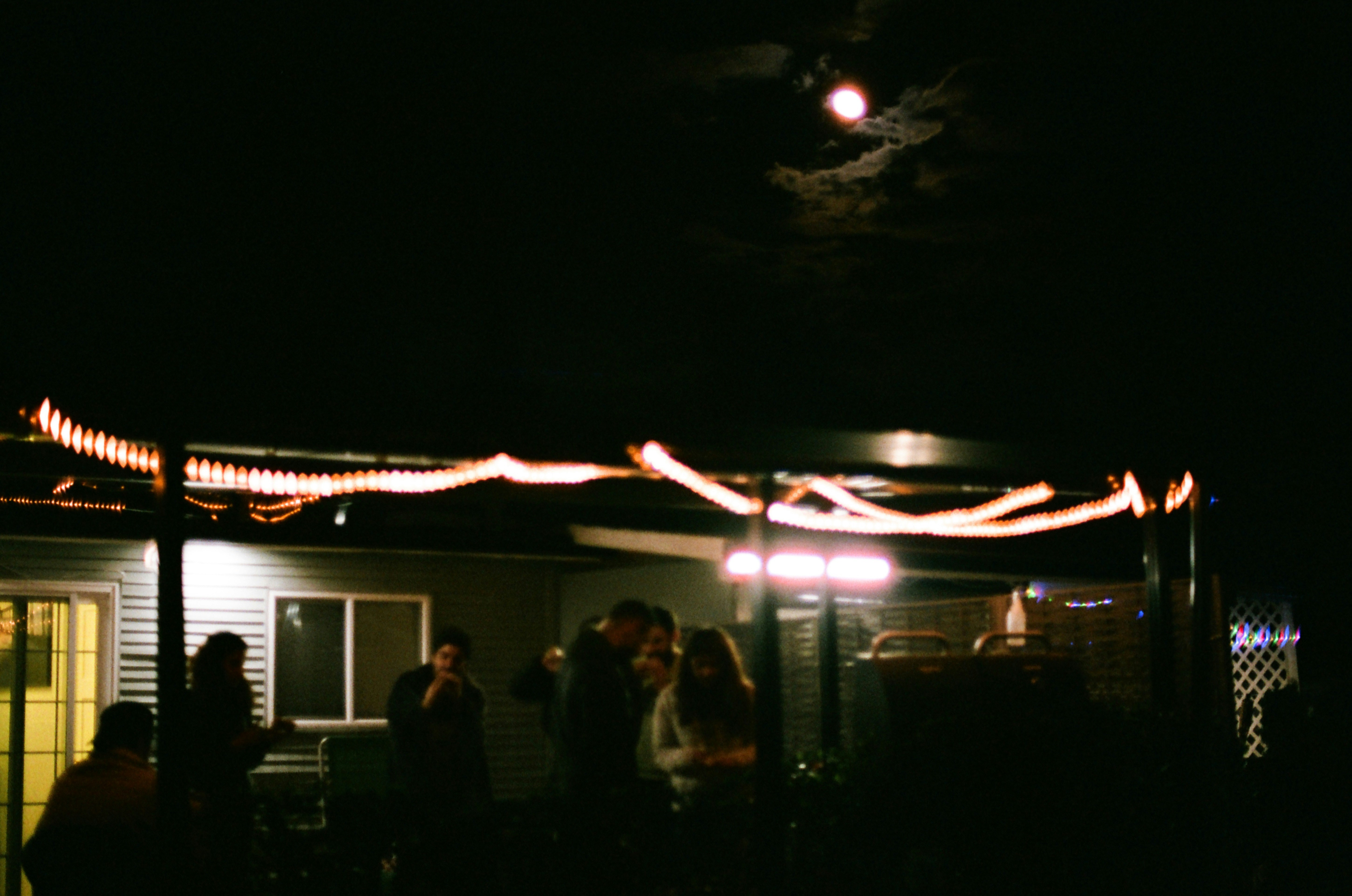 A group of people standing outside a house with a large firework in the ...