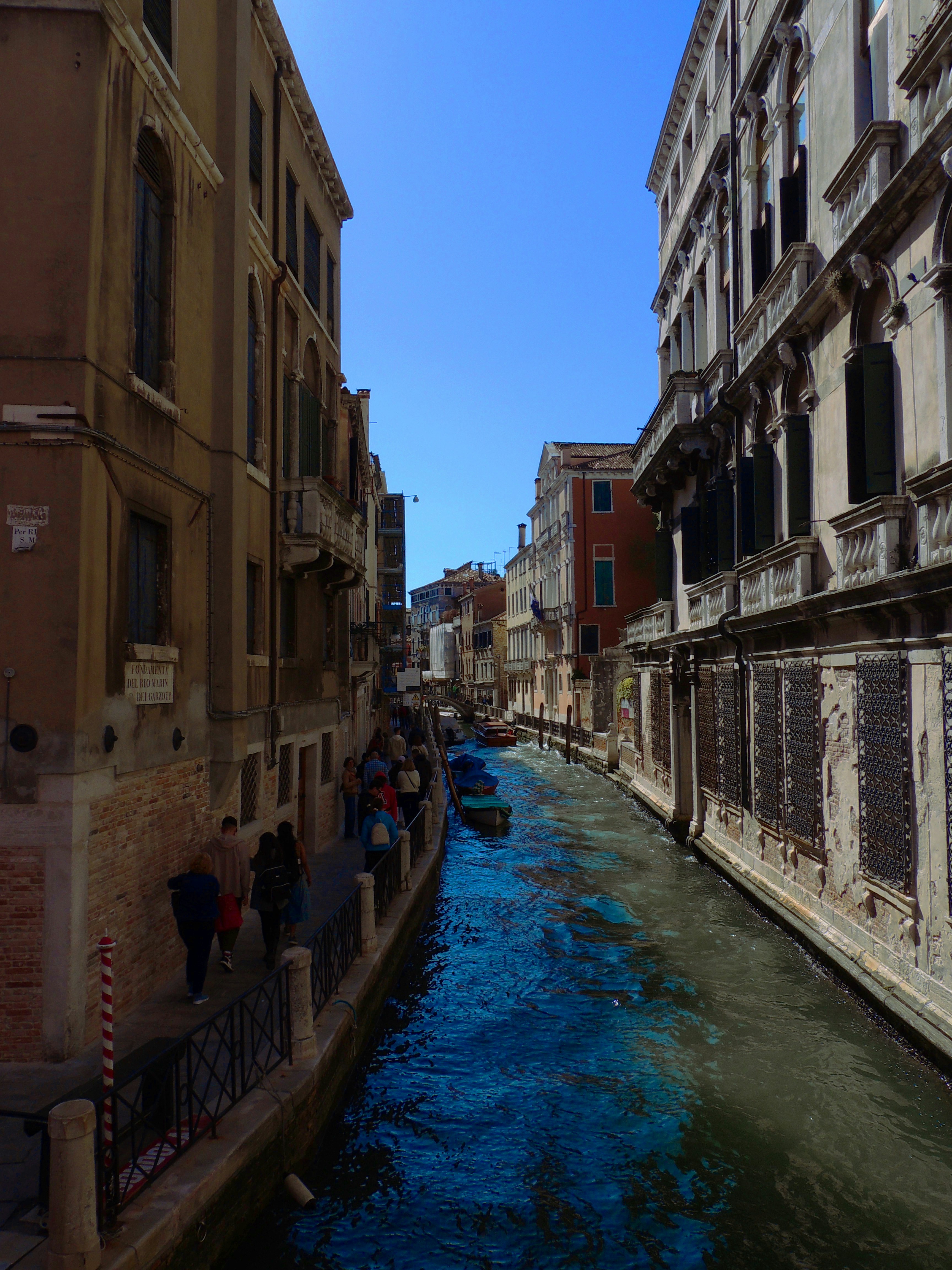 Azure Canalway: Sunlit Water Between Timeworn Palazzi in Venice