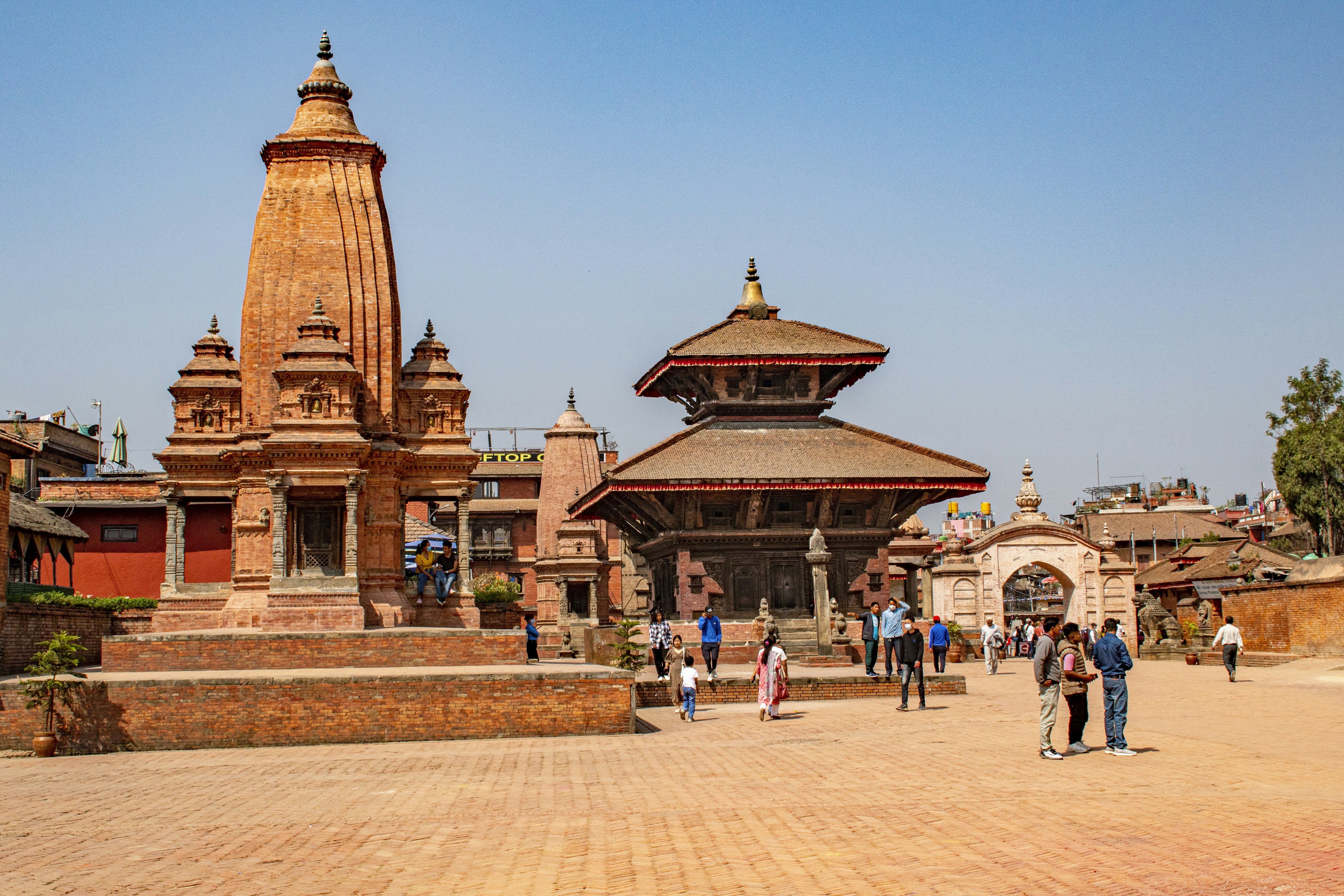 Historic temple complex featuring ornate structures and visitors exploring the site. The scene showcases a blend of cultural significance and architectural beauty.