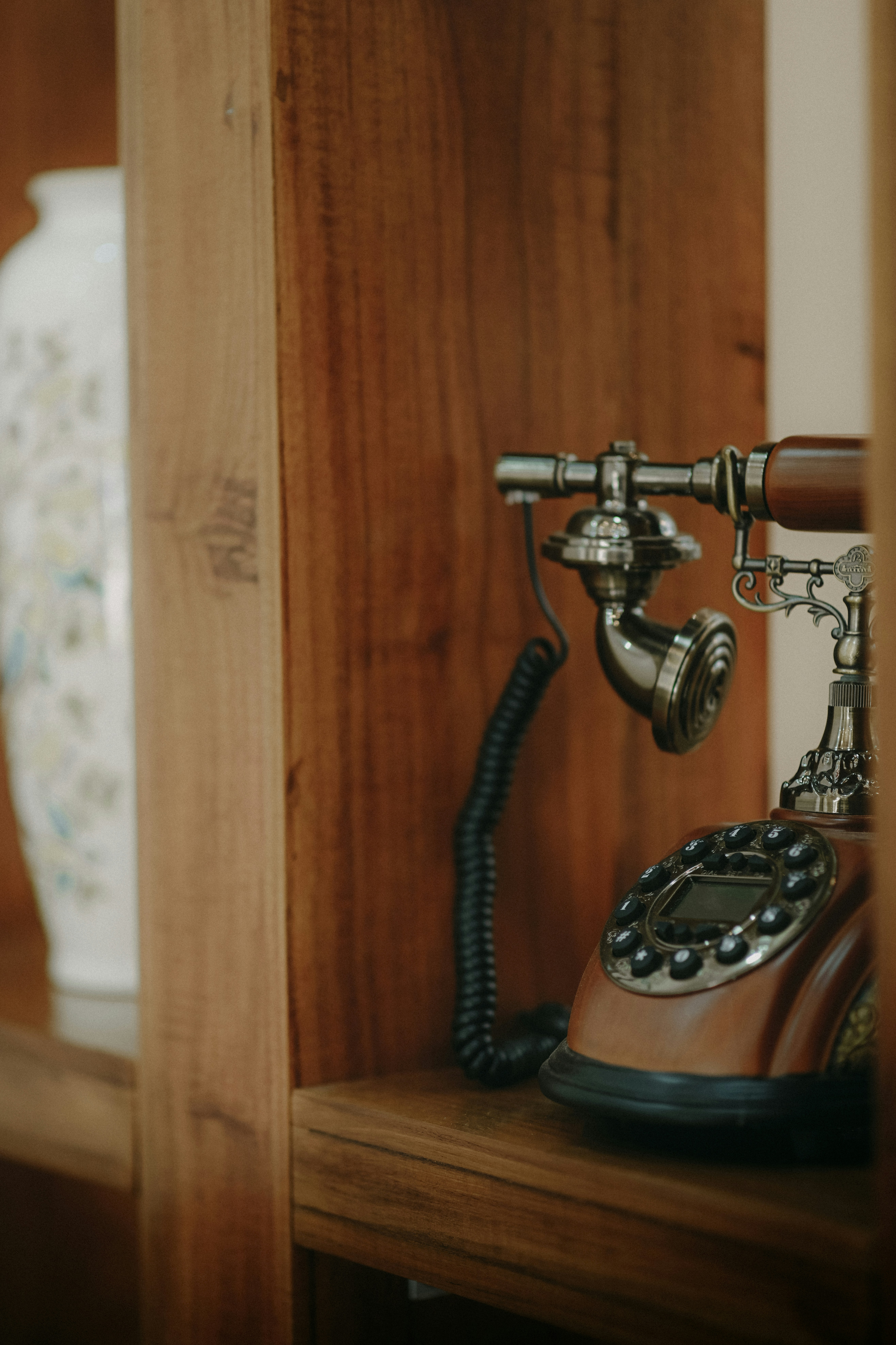 Dialed Nostalgia: A Vintage Rotary Phone on Warm Walnut Shelving