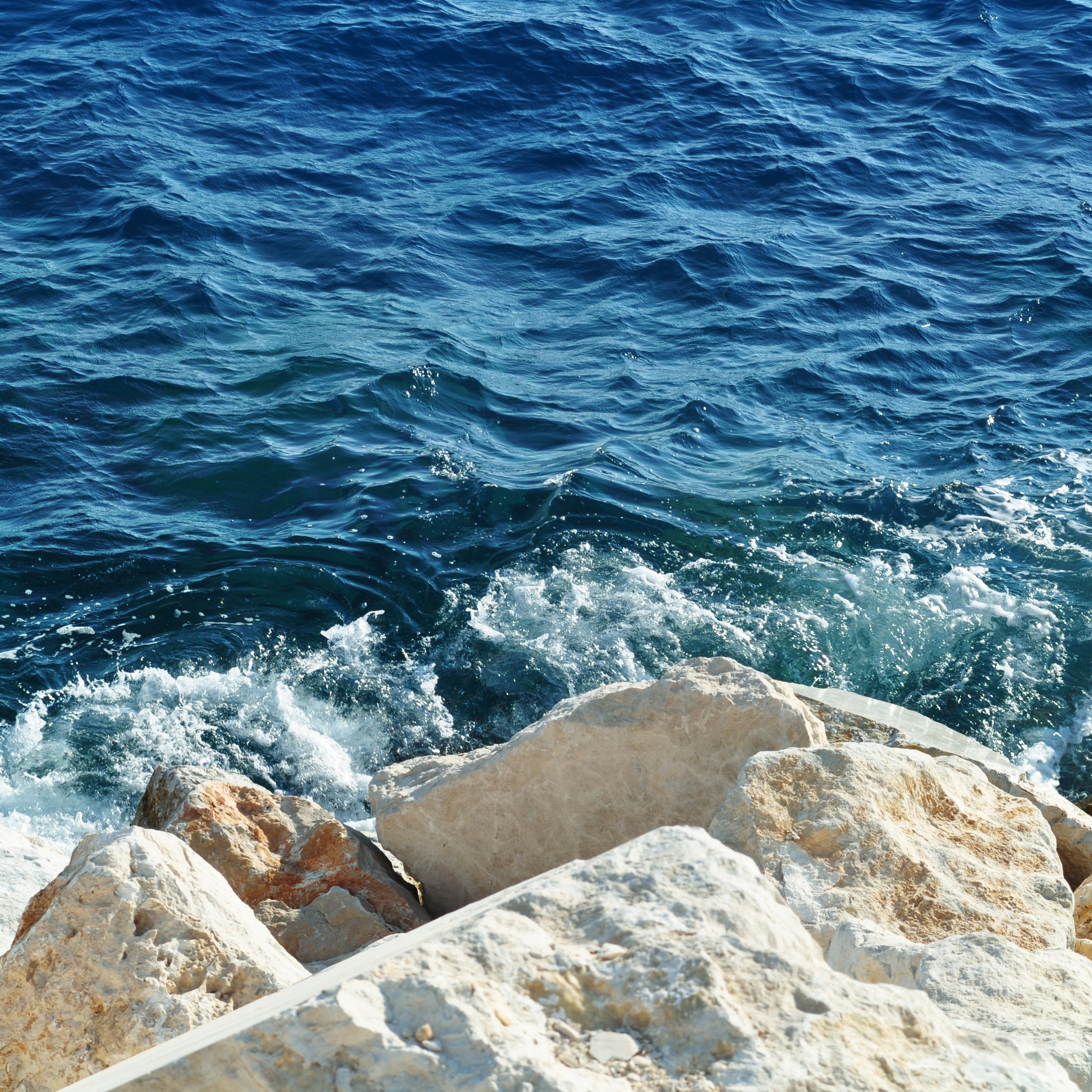 Rugged shoreline: sunlit rocks meet sapphire sea