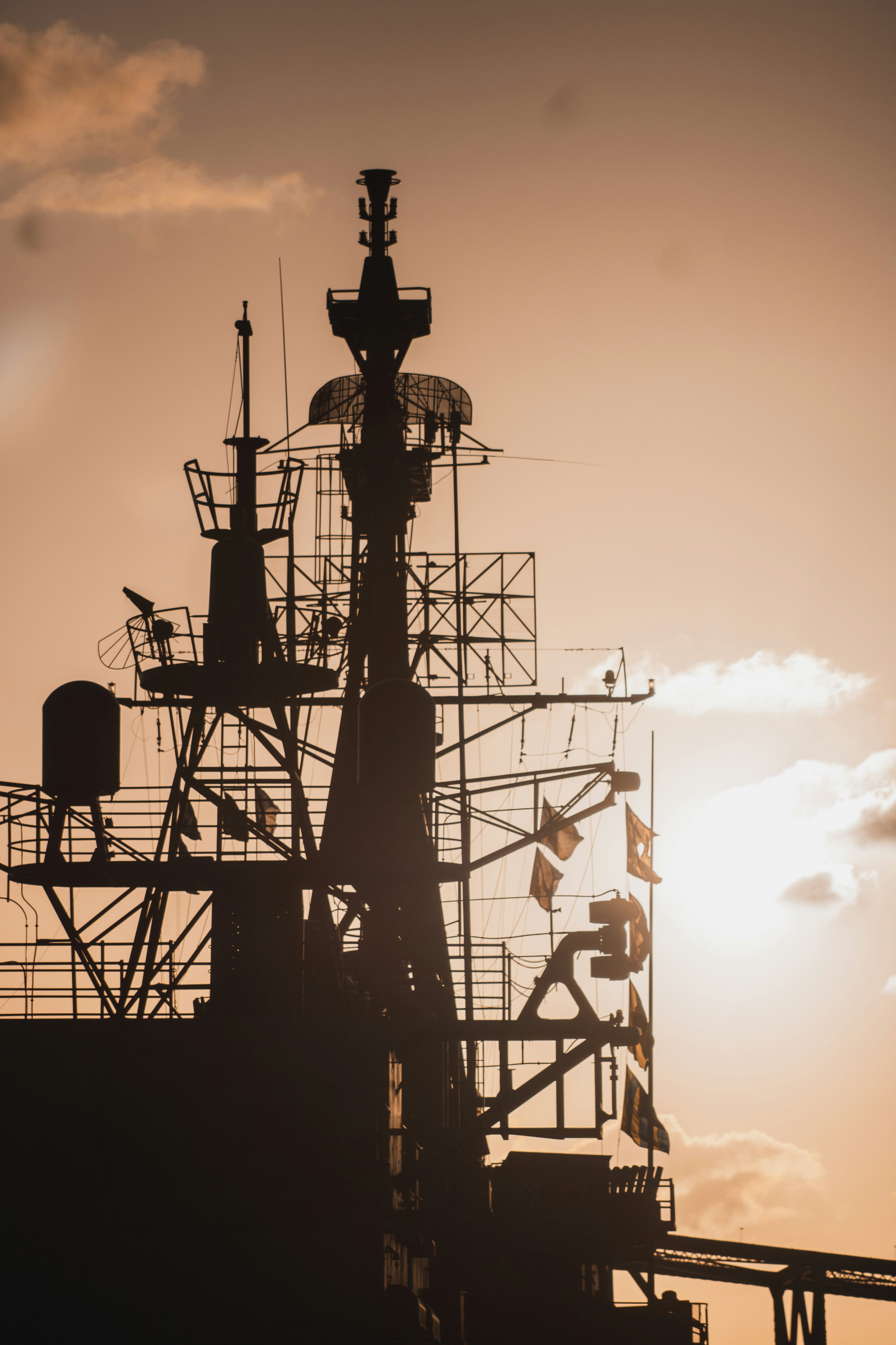 Dusk Mastwork: silhouettes of radar and antenna lattices against a copper sunset