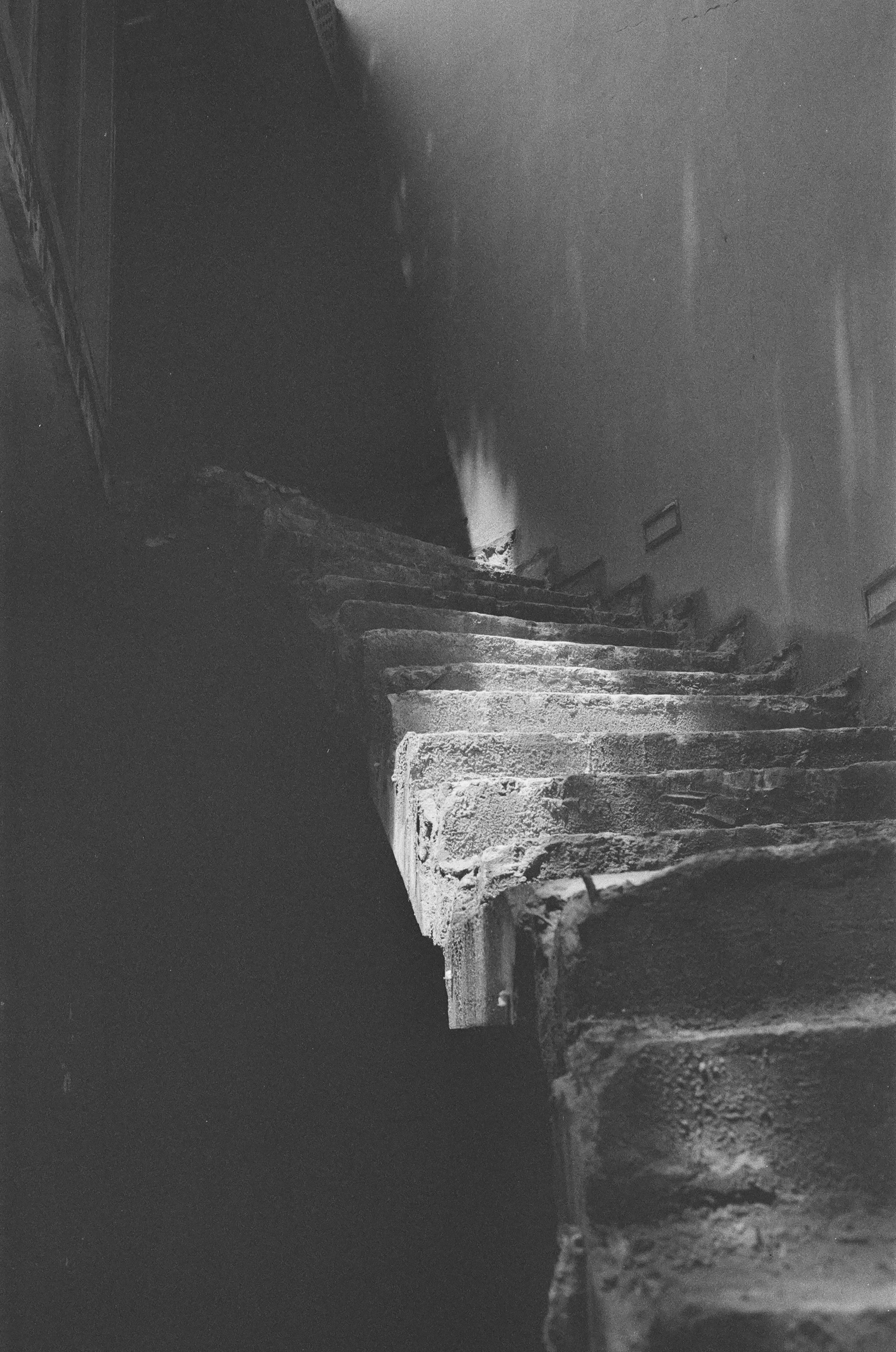 Weathered staircase leading into shadowy depths, illuminated by soft light filtering through. A blend of history and mystery.