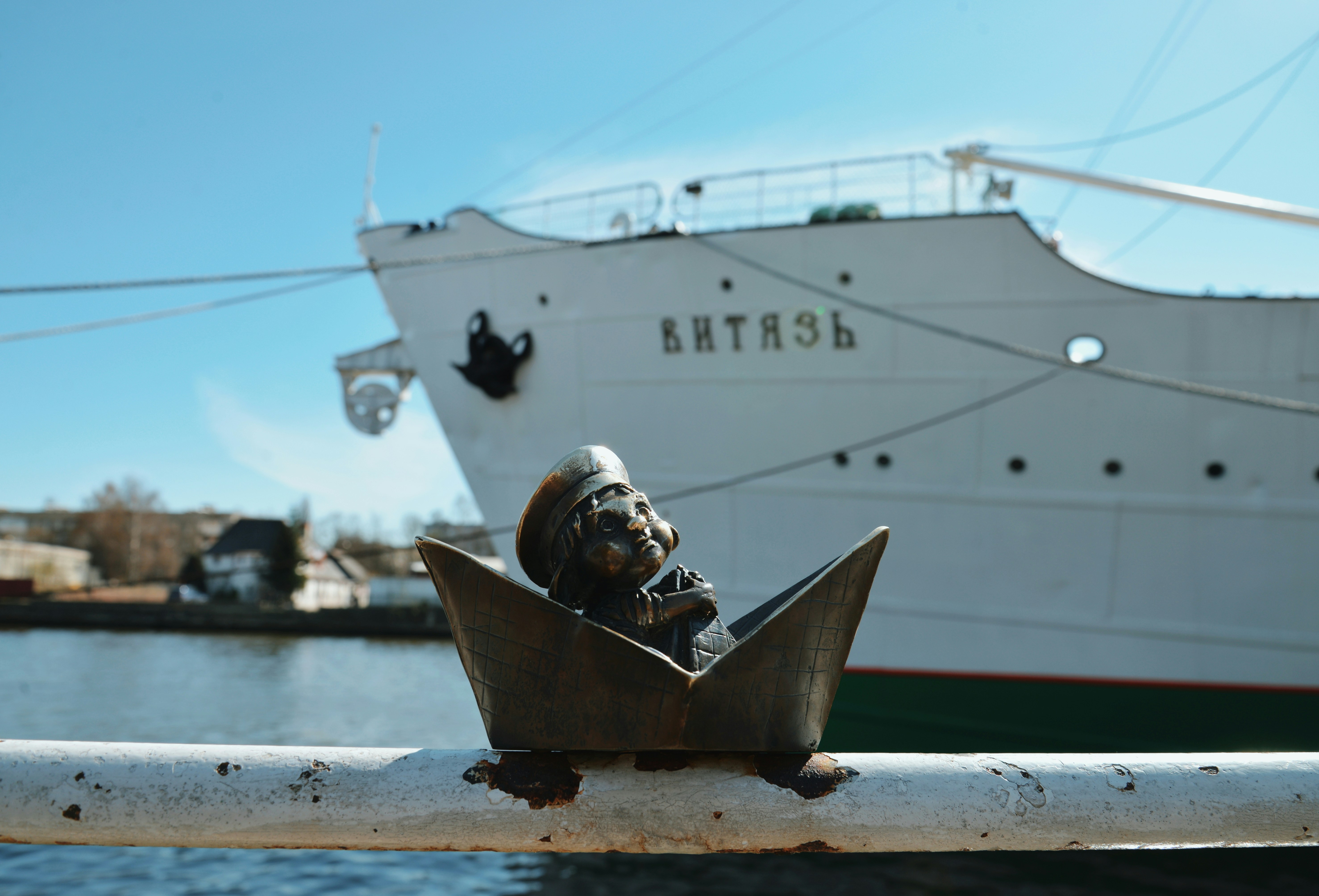 Harbor Sentinel: A Bronze Anchor Framed by a Distant White Vessel