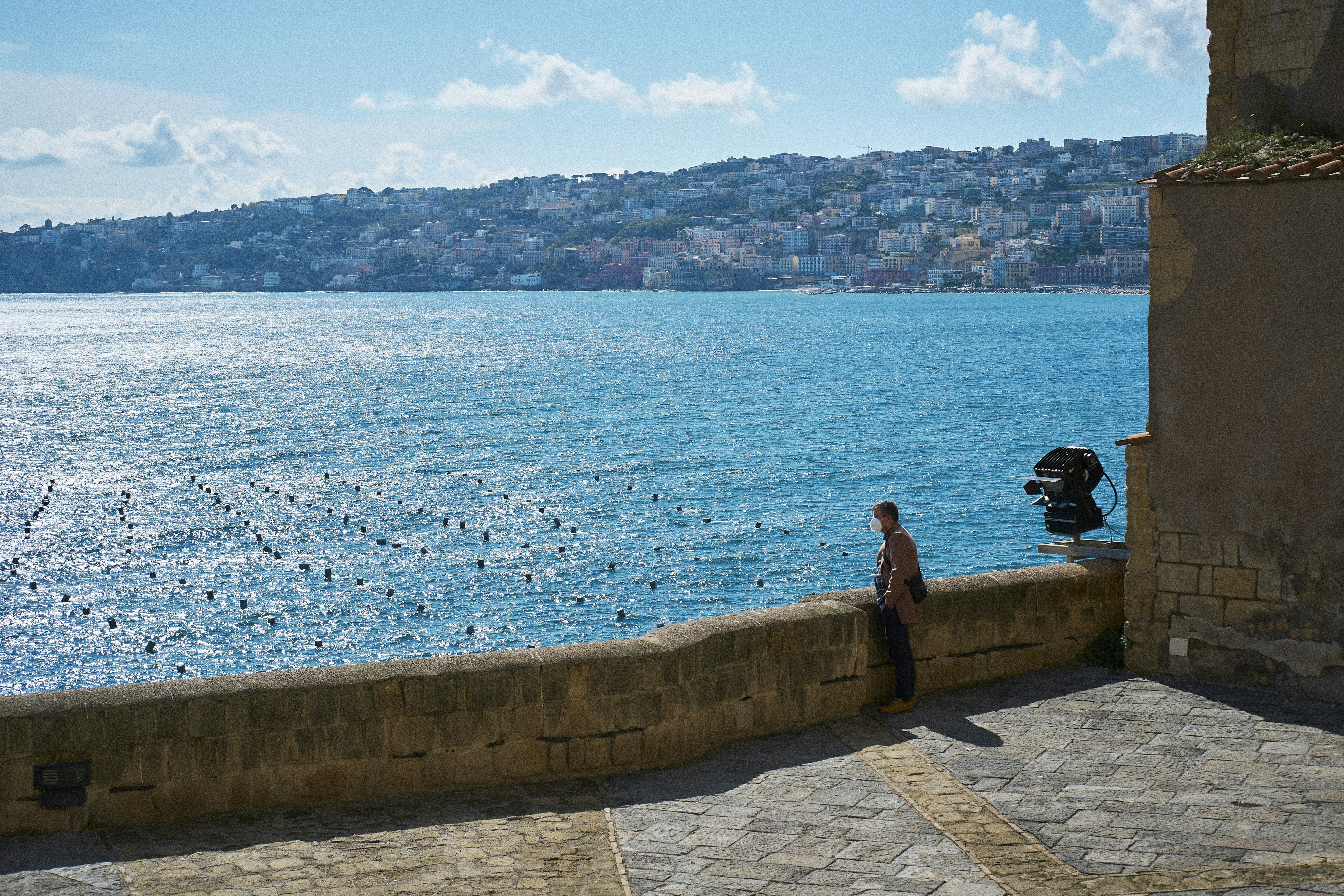 Harbor Wall: A Lone Observer by the Turquoise Sea