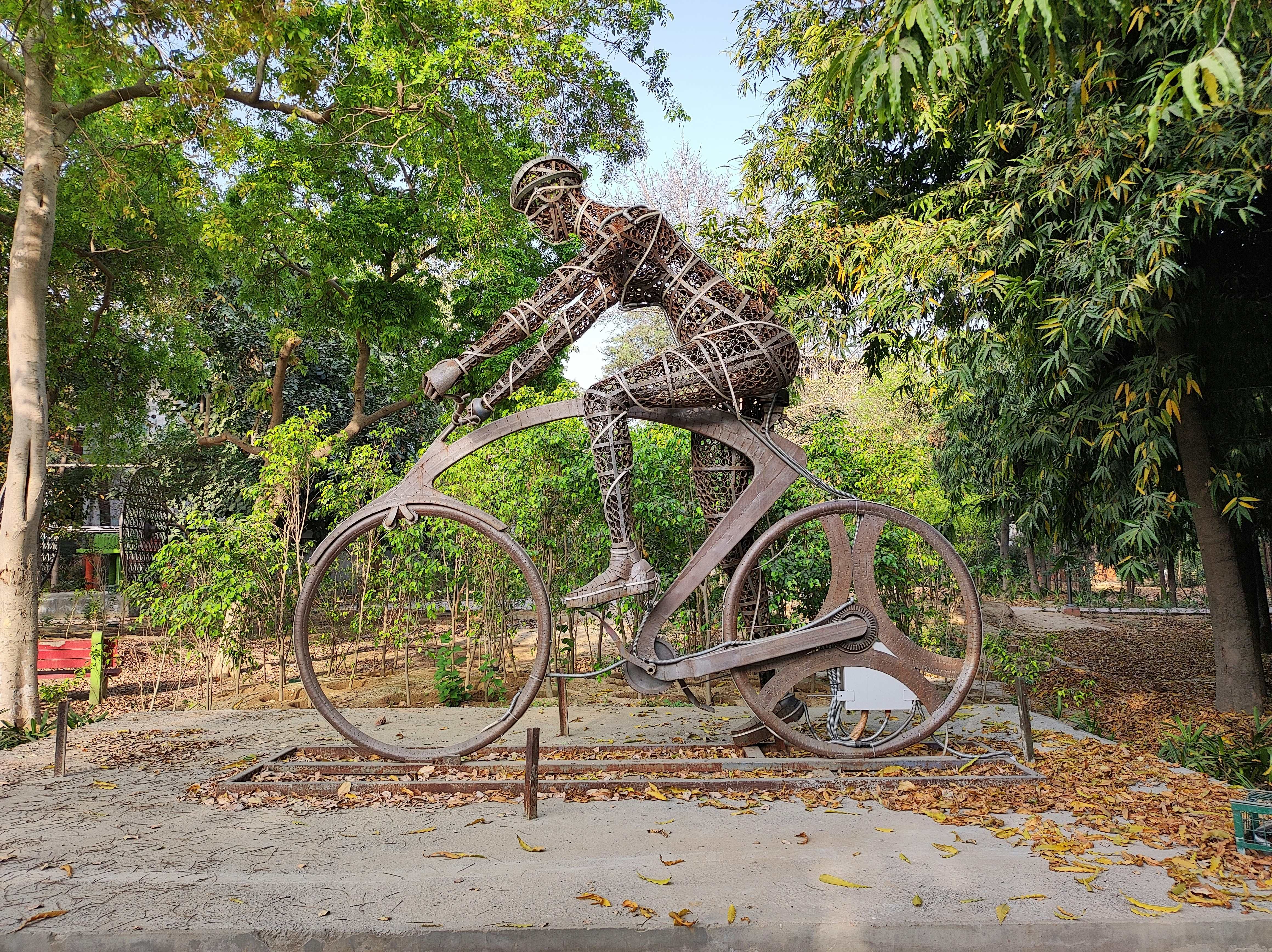 Iron Rider in the Park: A Metallic Cyclist Duel Against Autumn