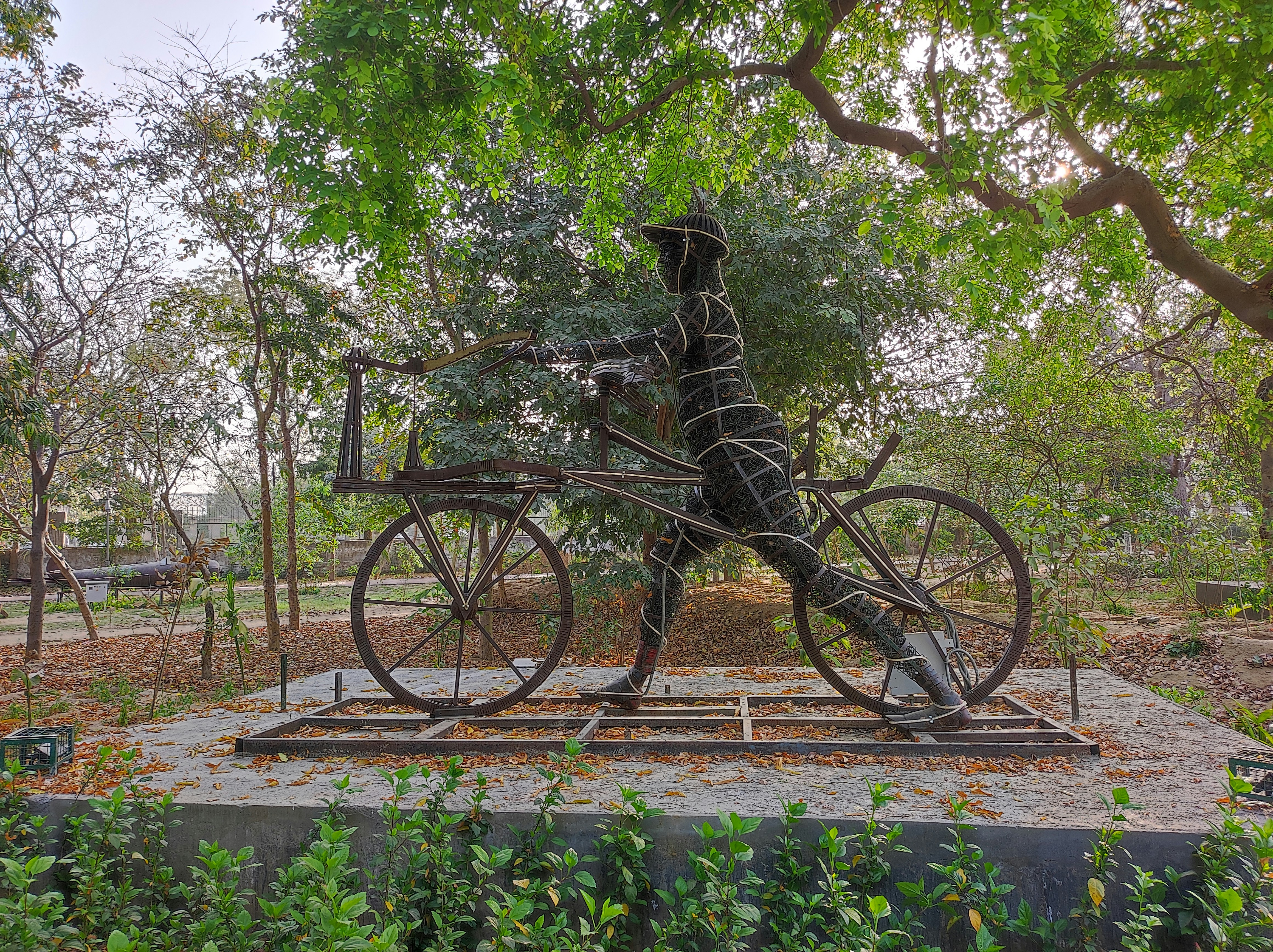Rusted Cyclist Monument Amid the Quiet Orchard