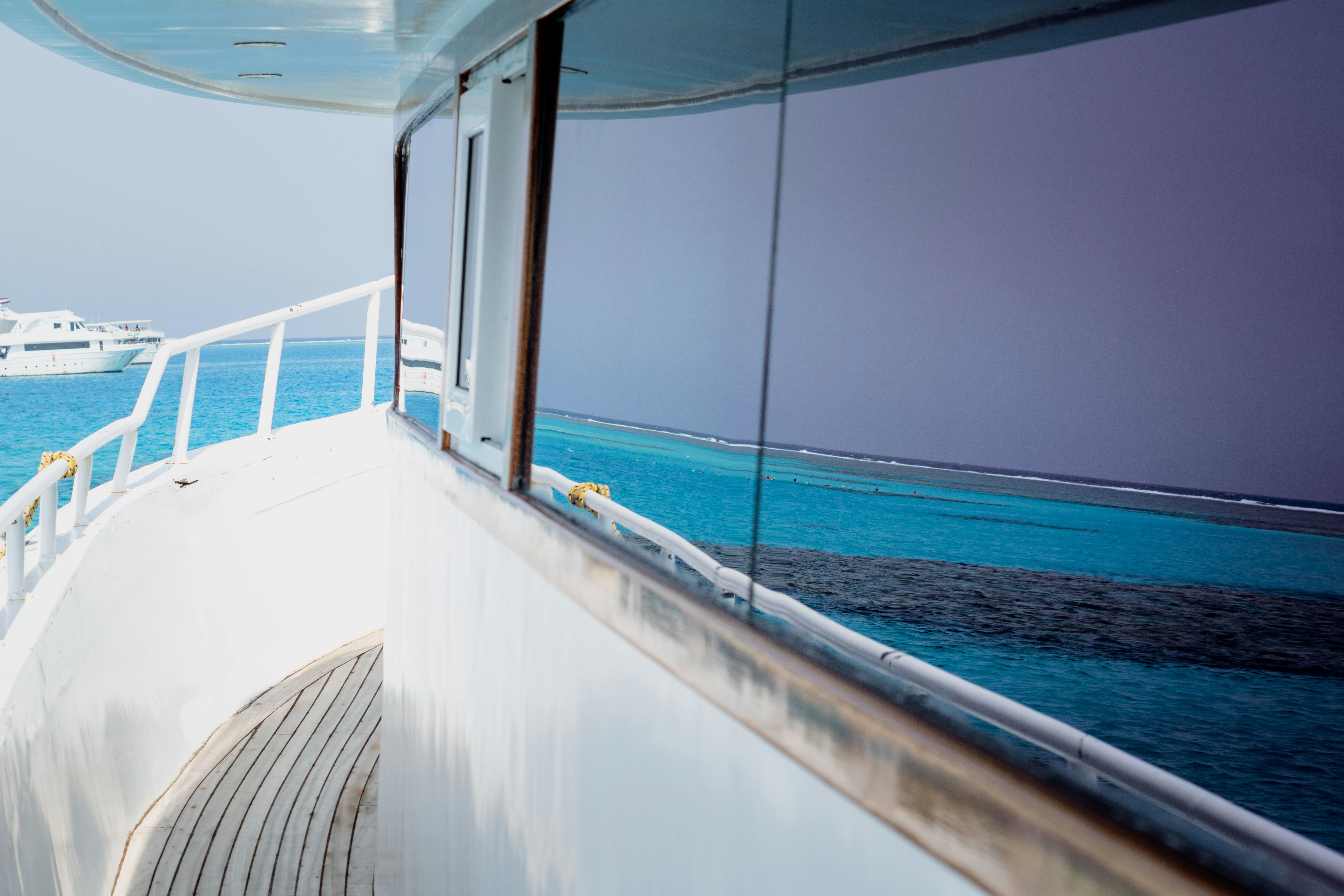 Curved deck of a yacht reflecting vibrant blue waters under a clear sky. The image highlights the interplay between the boat's structure and the sea's tranquility.