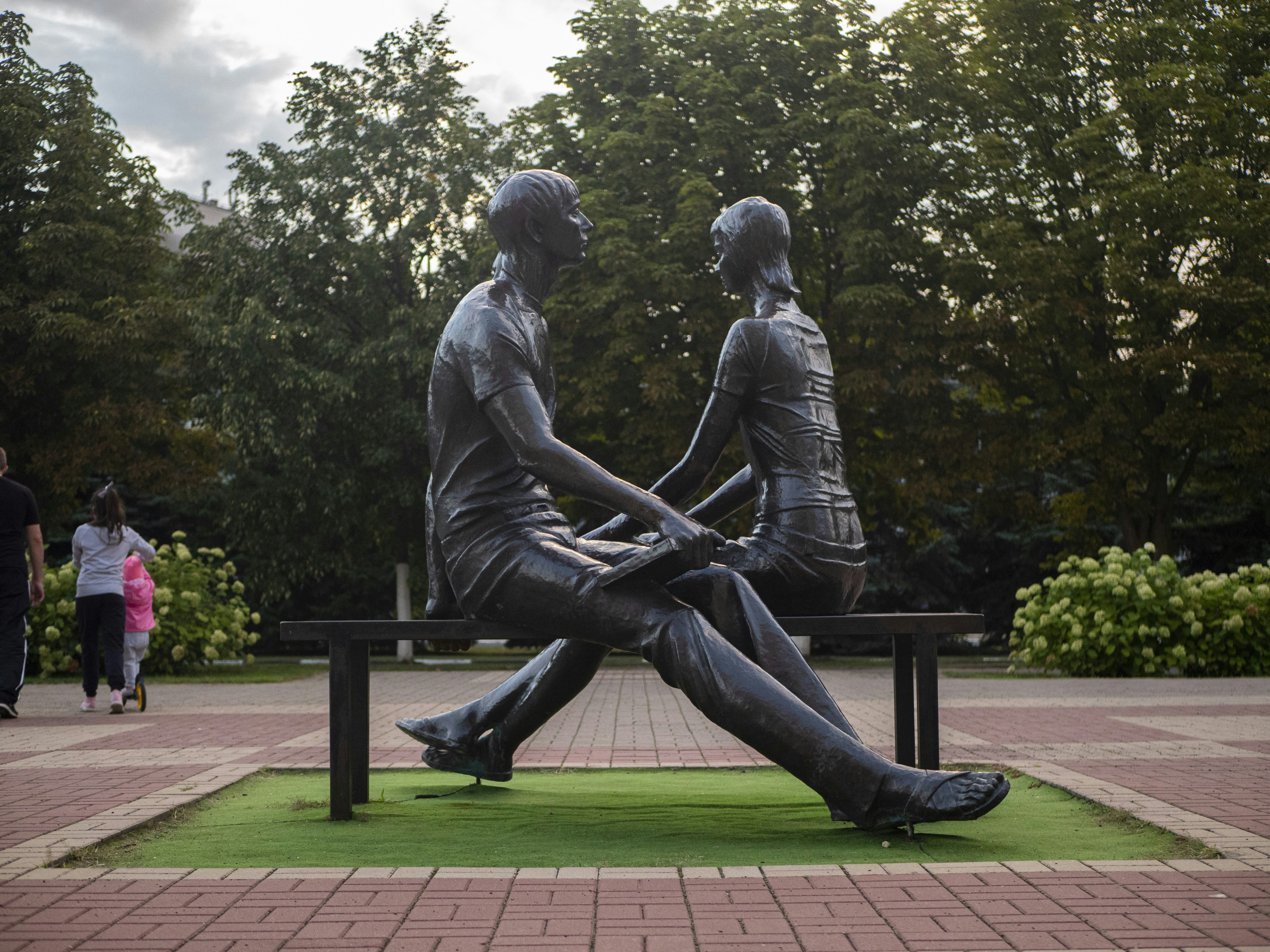 Interlocked Figures on a Green Pedestal in a Quiet Park