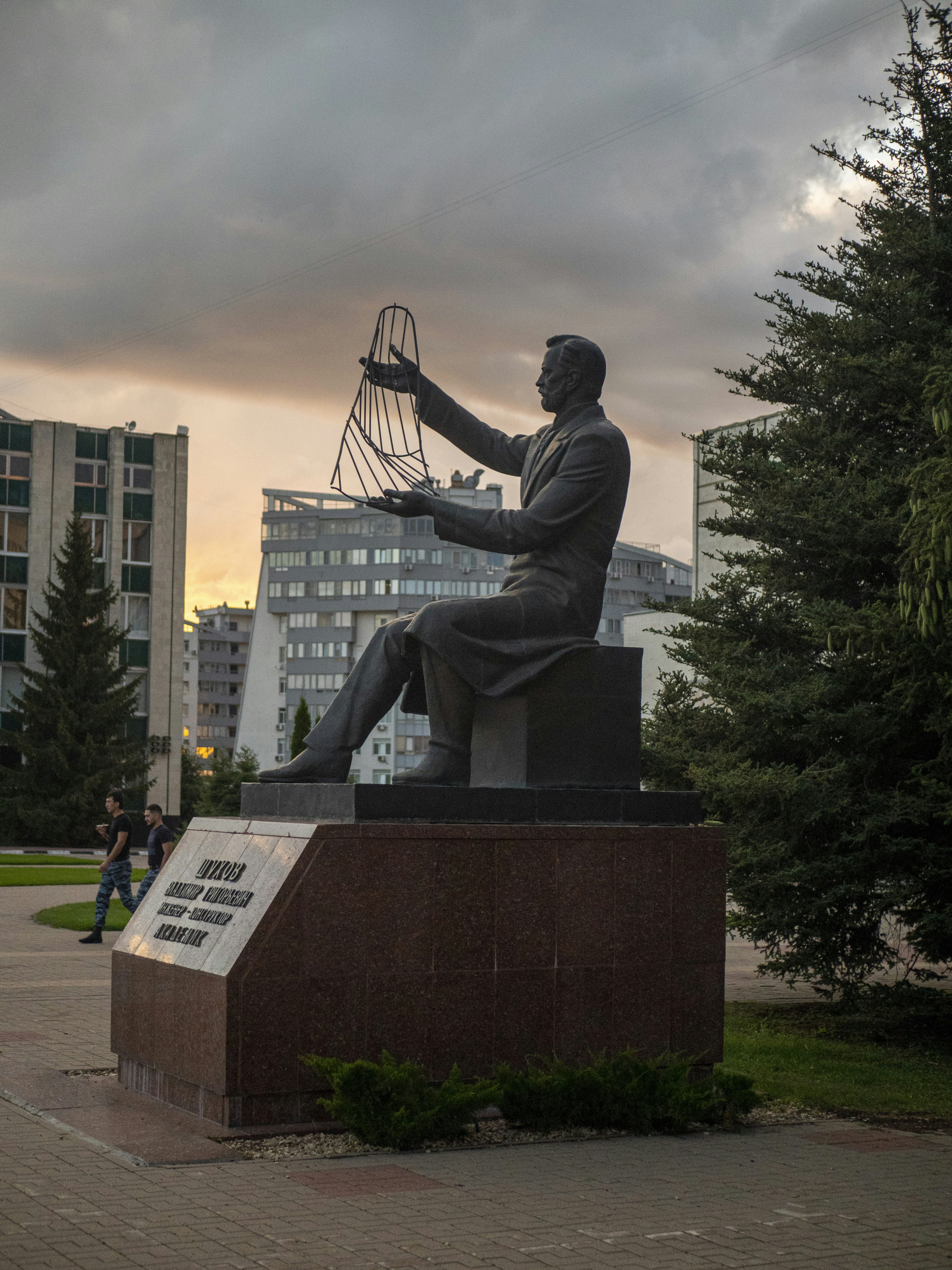 Une statue d’un homme assis sur un banc devant un arbre photo – Photo ...