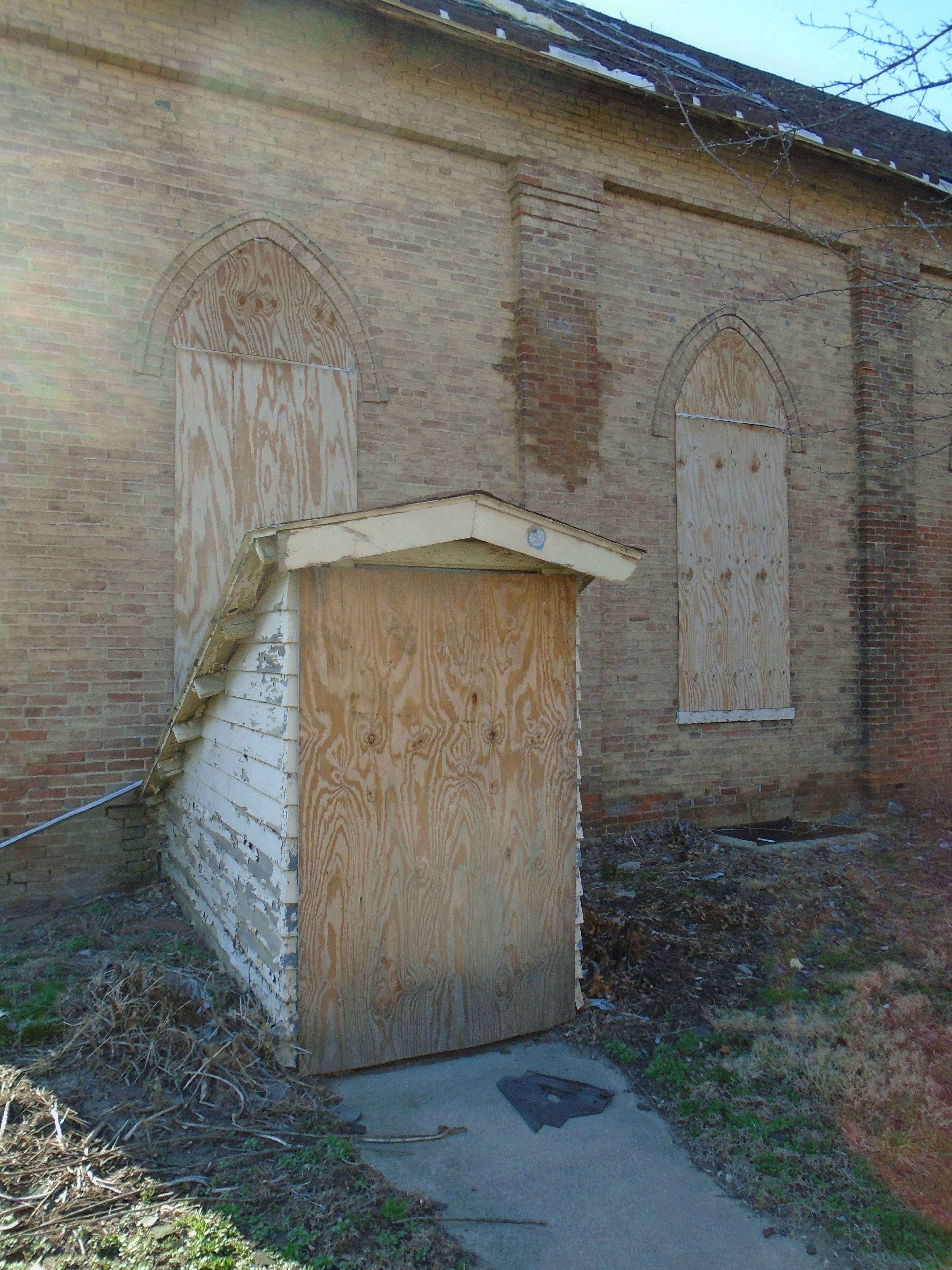 Arched Silence: A boarded façade and a lone shed