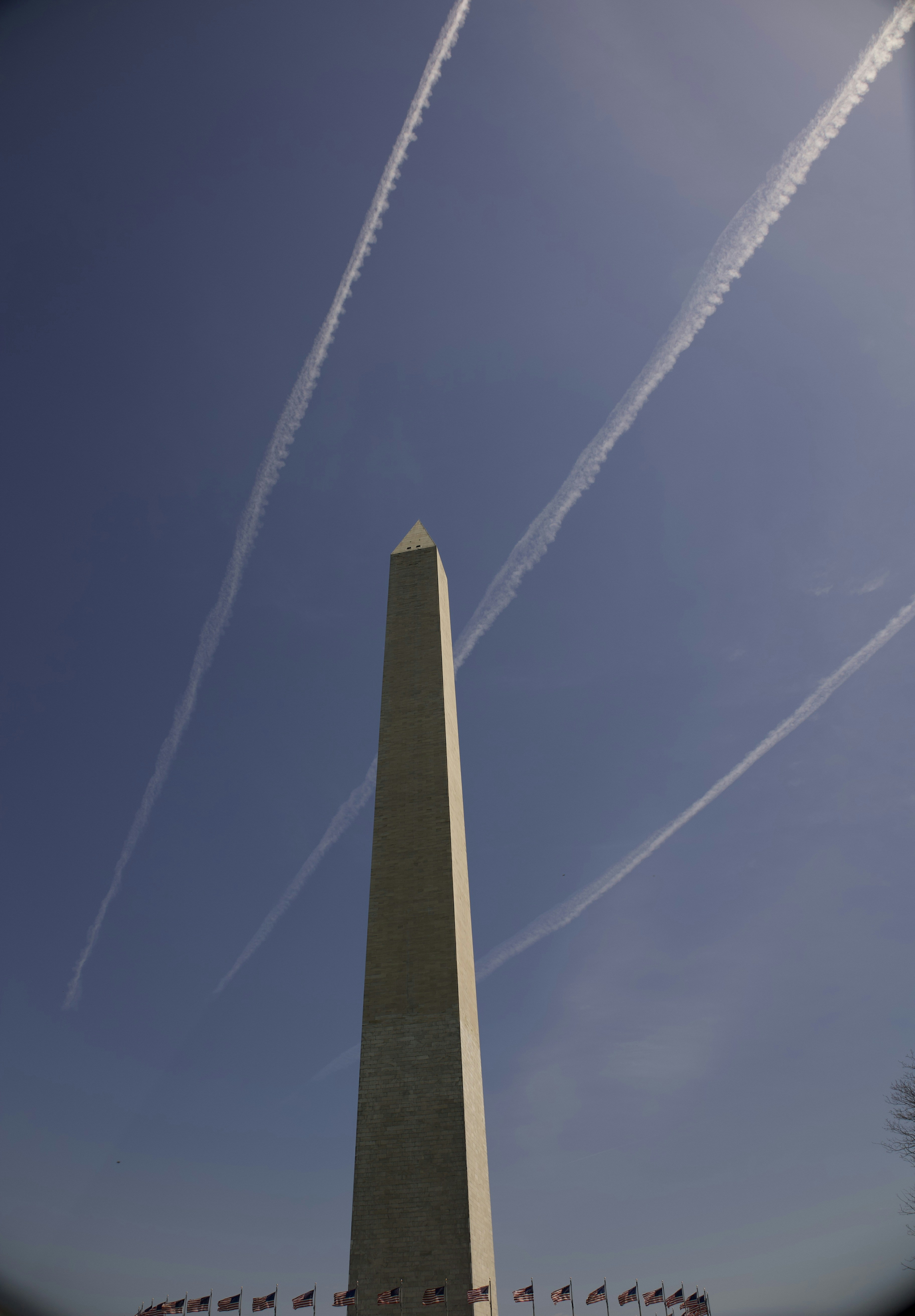 A Skyward Tribute: The Monument Against a Canvas of Contrails