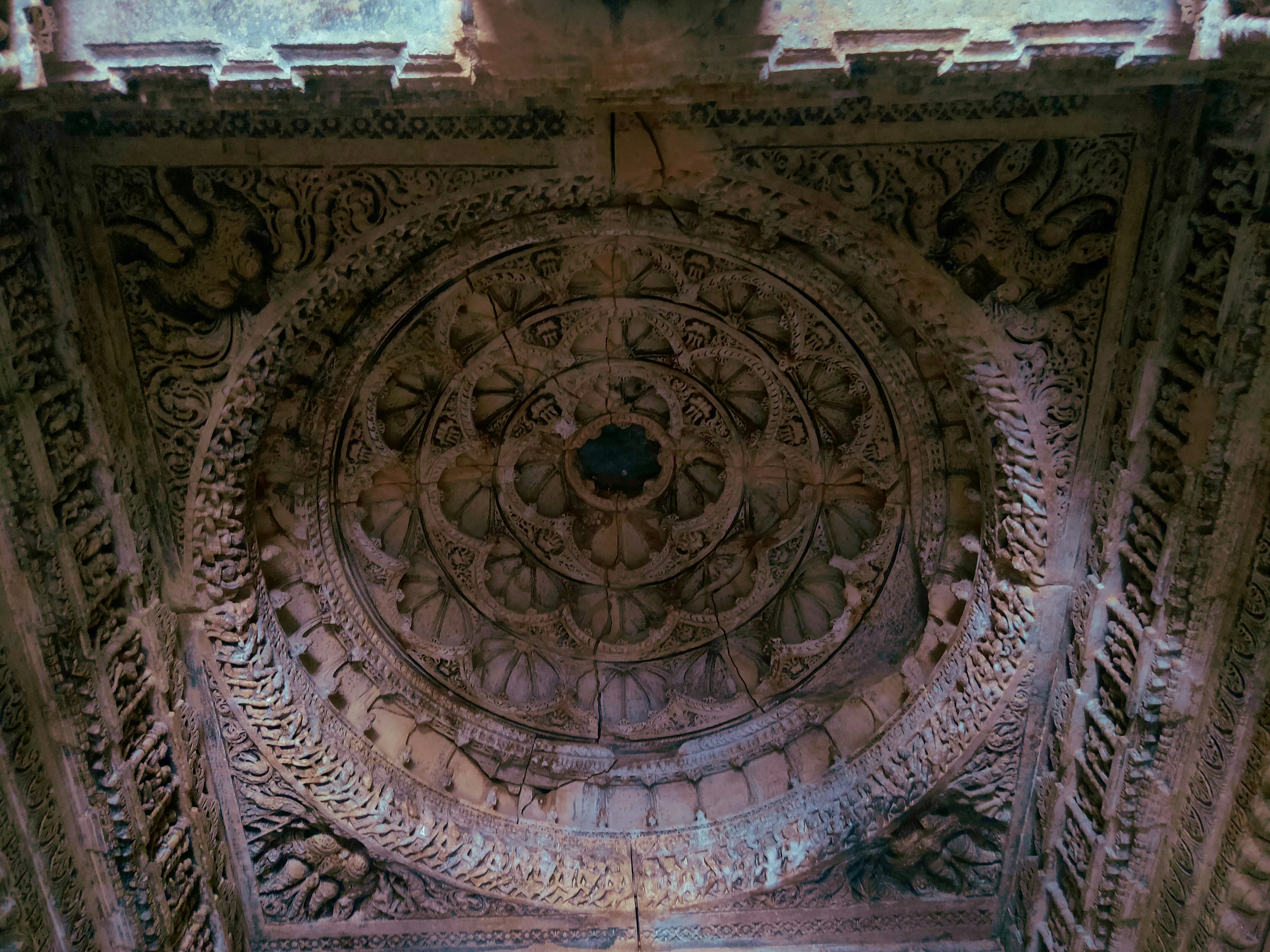 Elaborately carved ceiling featuring a central mandala surrounded by floral motifs and intricate designs.
