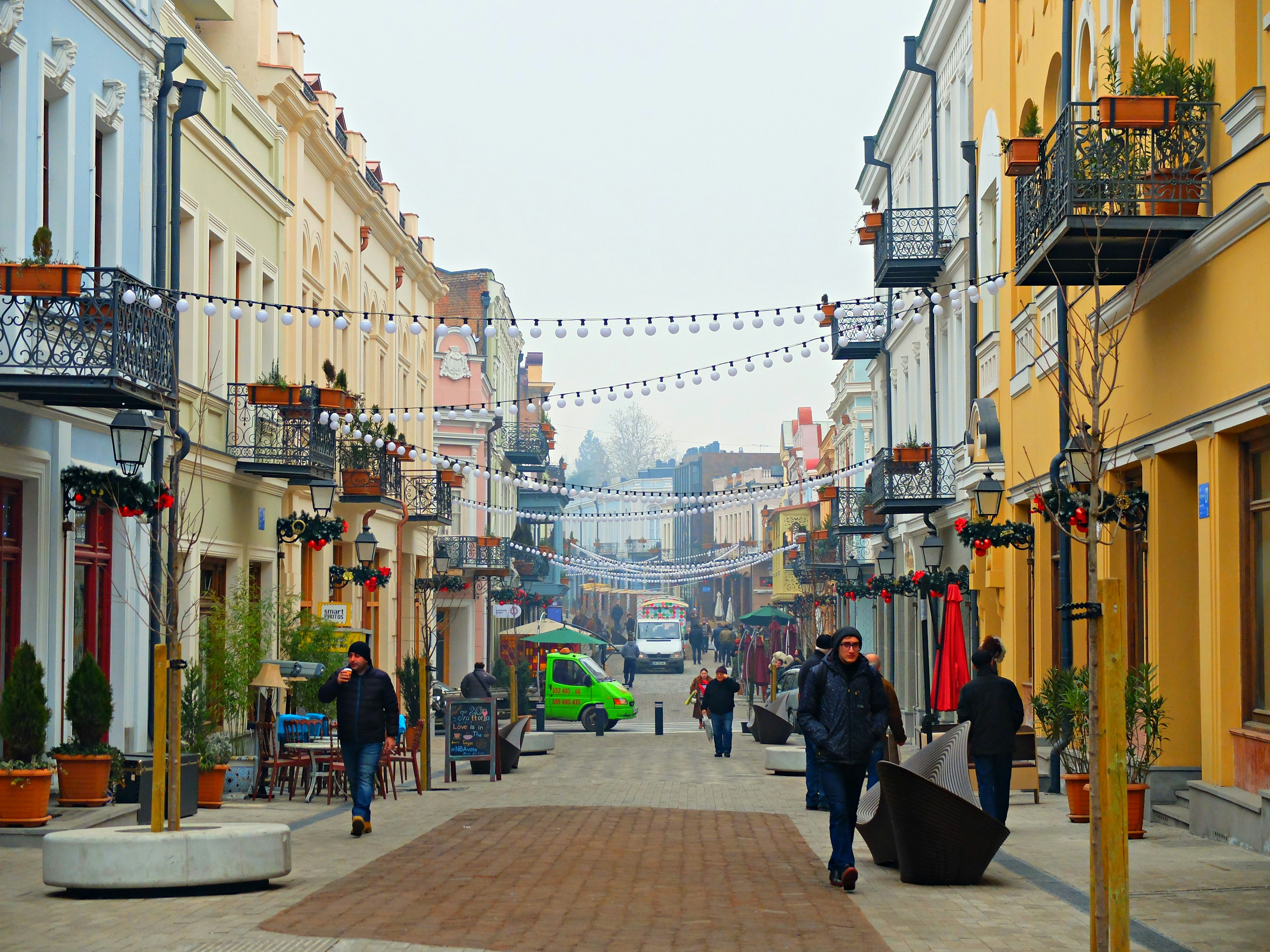 Charming pedestrian street lined with colorful buildings and festive decorations, bustling with people enjoying the atmosphere.