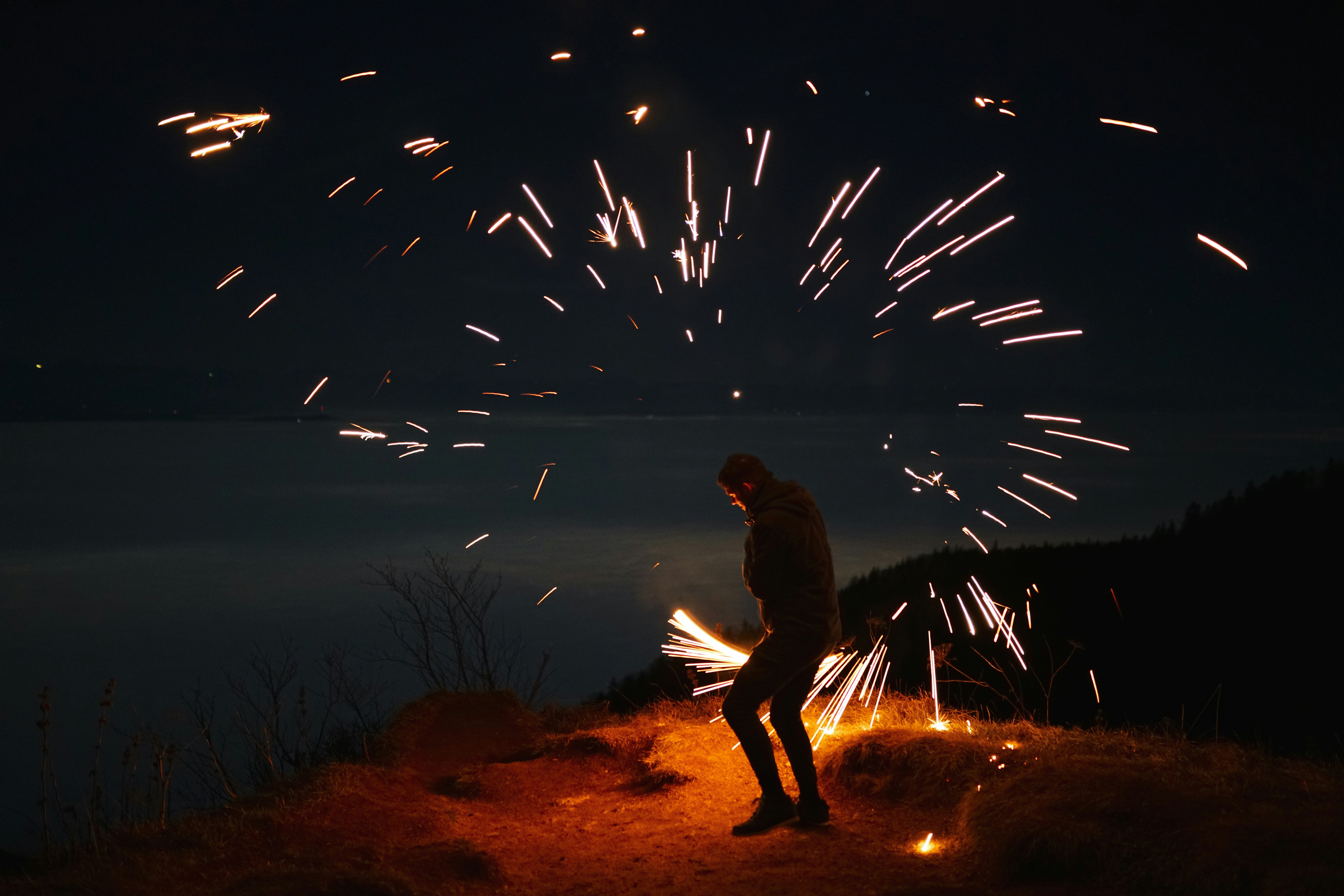Midnight Firewalker: A solitary silhouette dances with sparks along a cliff edge