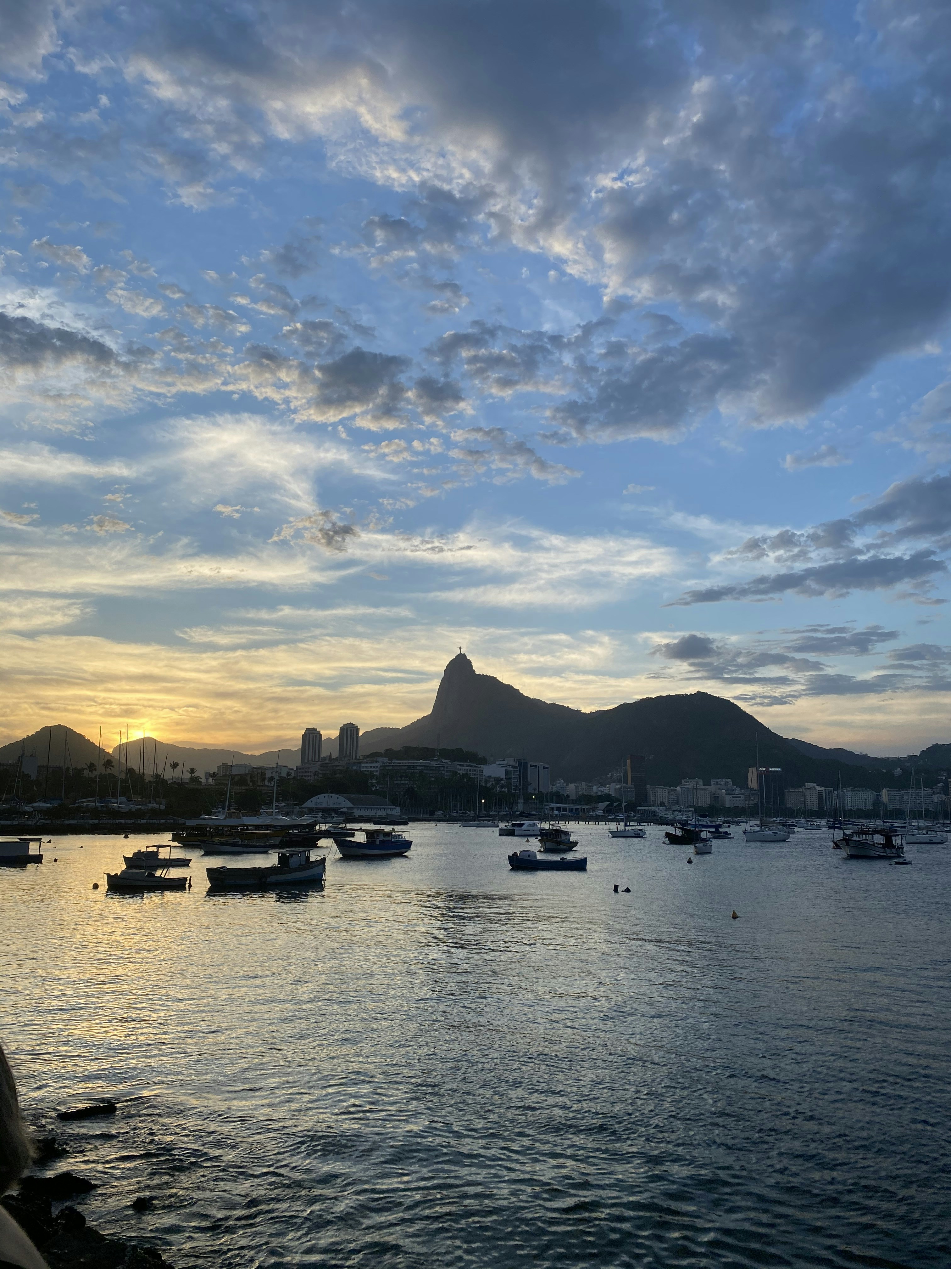 Dusk Harbor: Sailboats Scatter Beneath a Crowned Peak