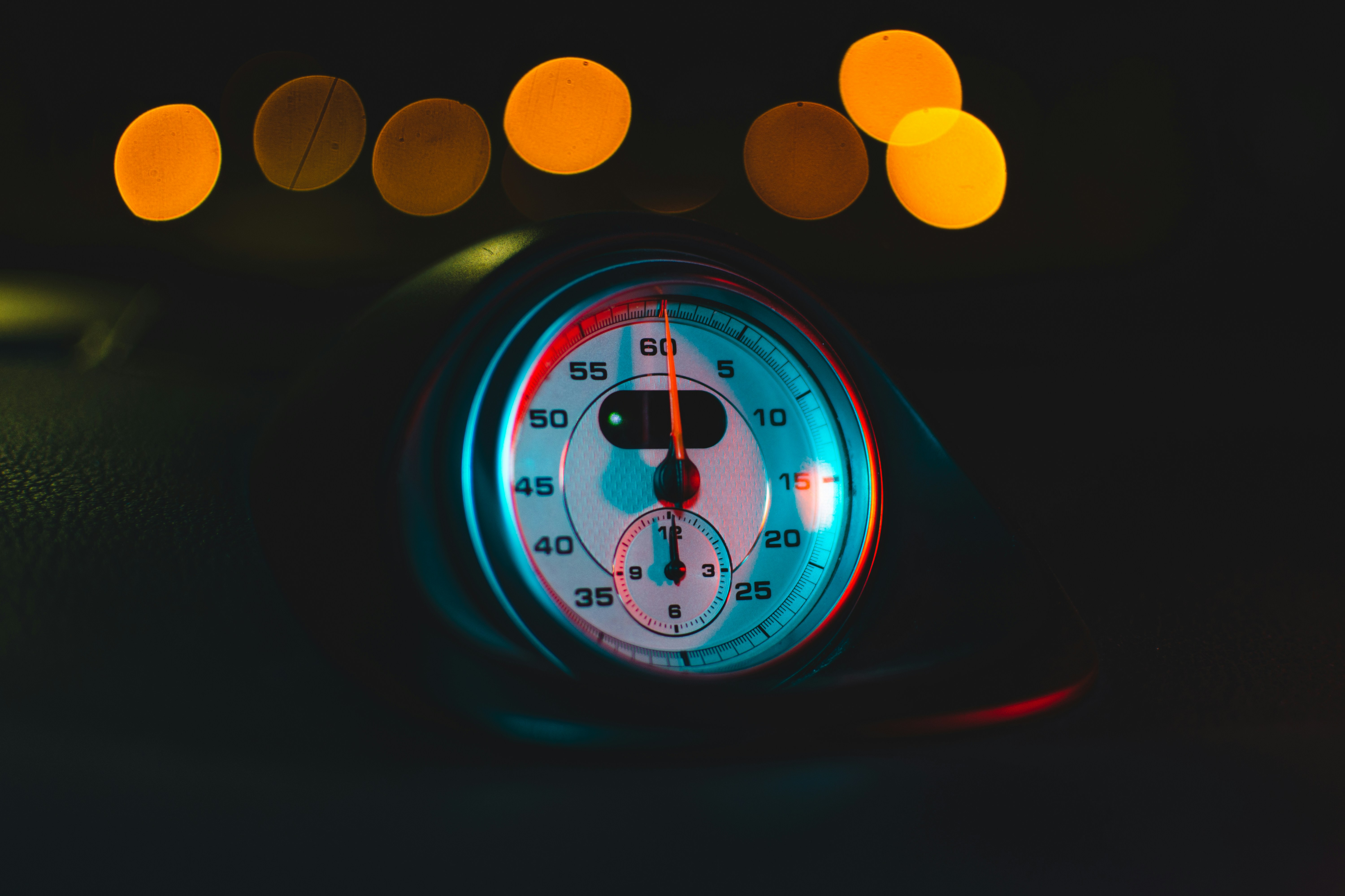 Neon Dial at Night: A Close-Up of a Car Tachometer Amid City Bokeh