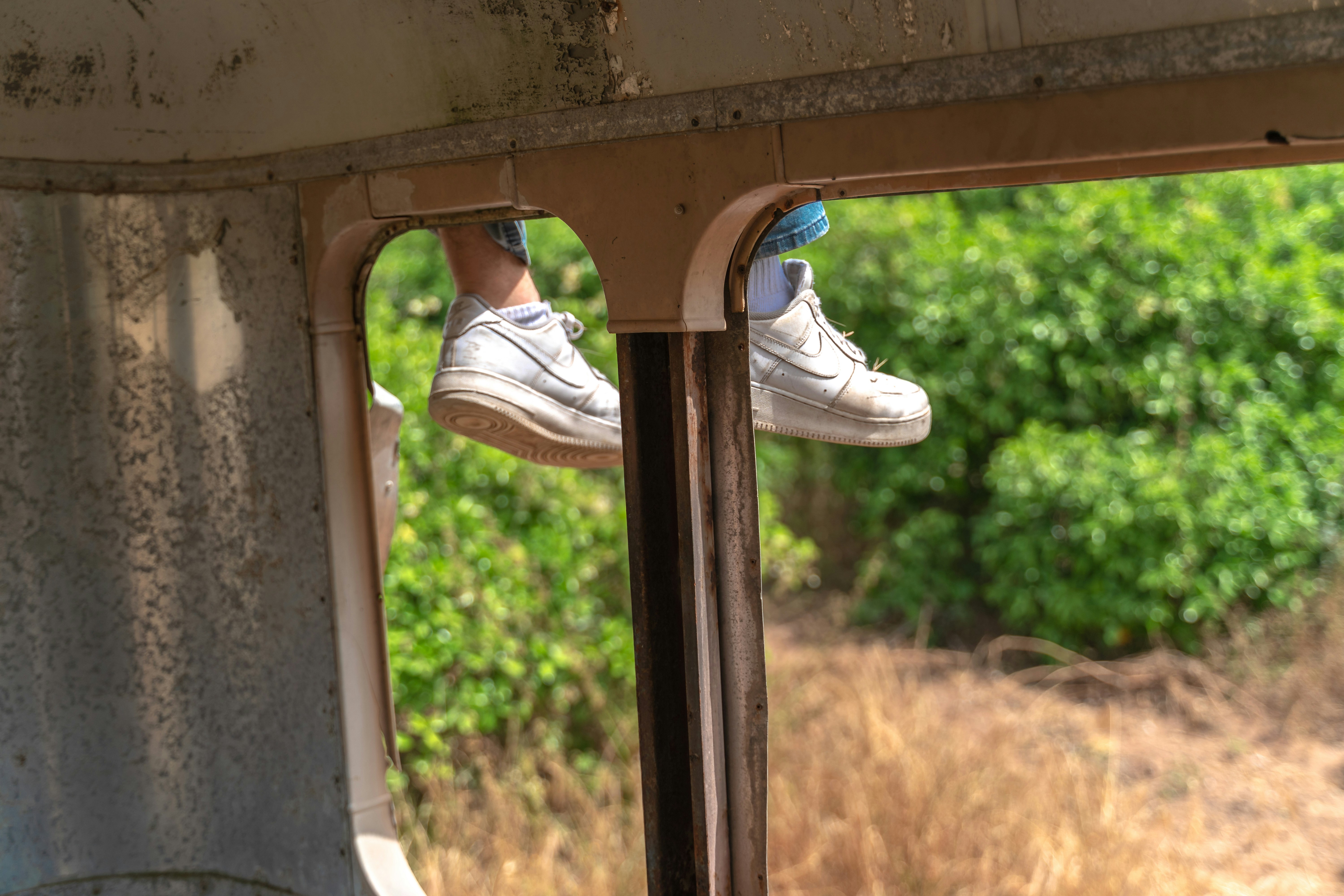 Sneakers Dangling Through a Rusted Train Window