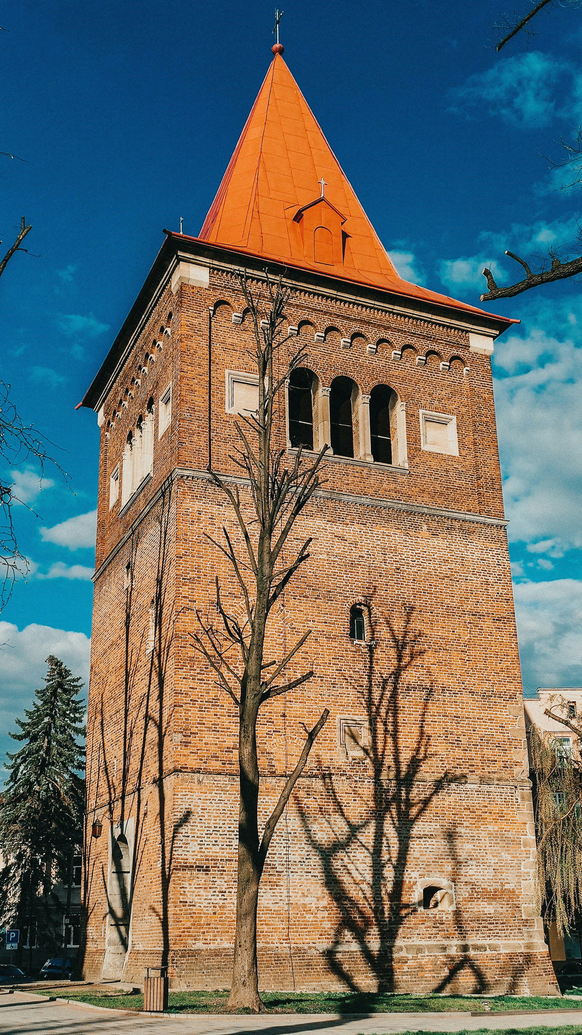 Brick Bell Tower Under Blue Sky with Bare Trees