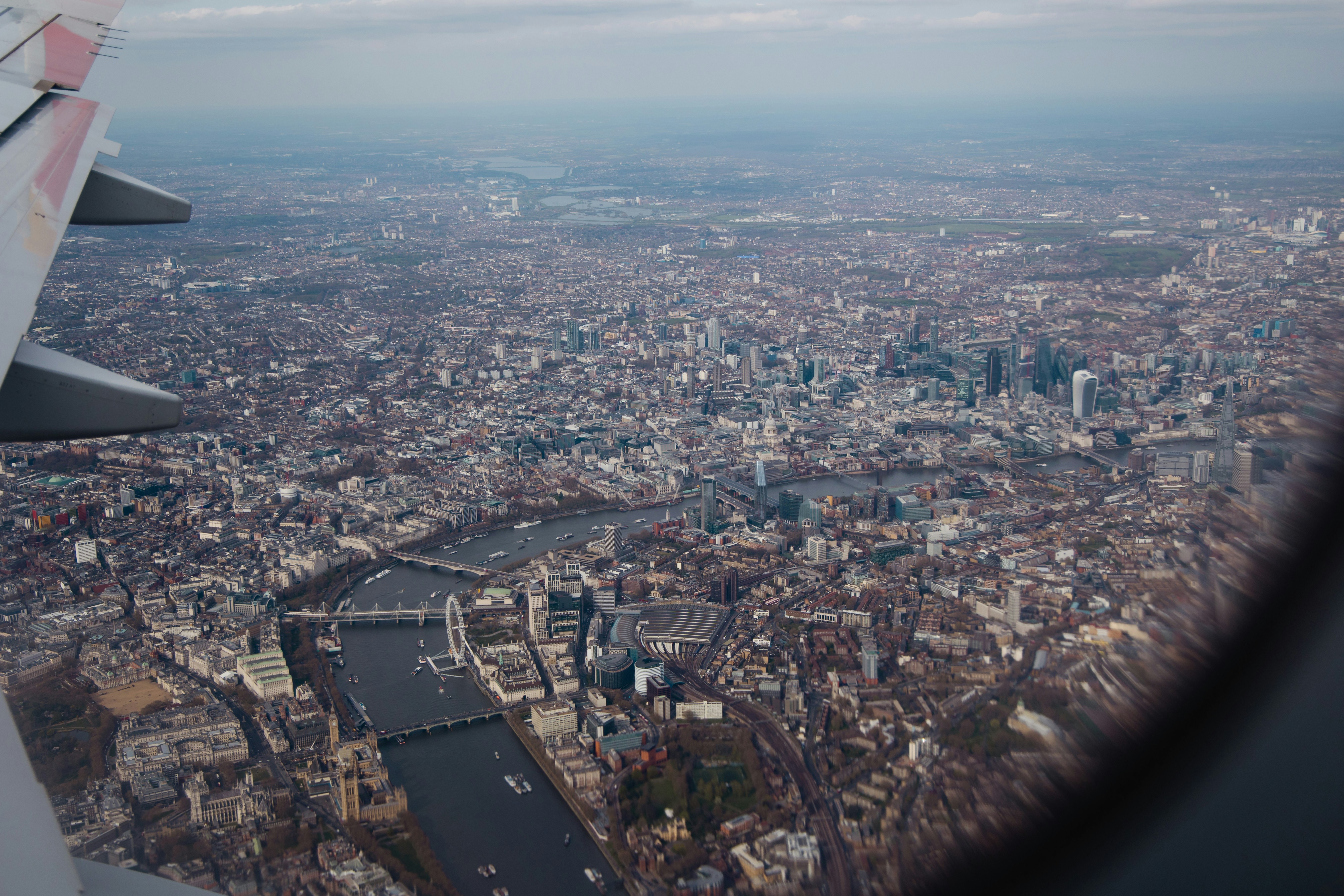 Aerial perspective showcasing the intricate layout of London, featuring the River Thames and iconic landmarks. Captured from an aircraft window.
