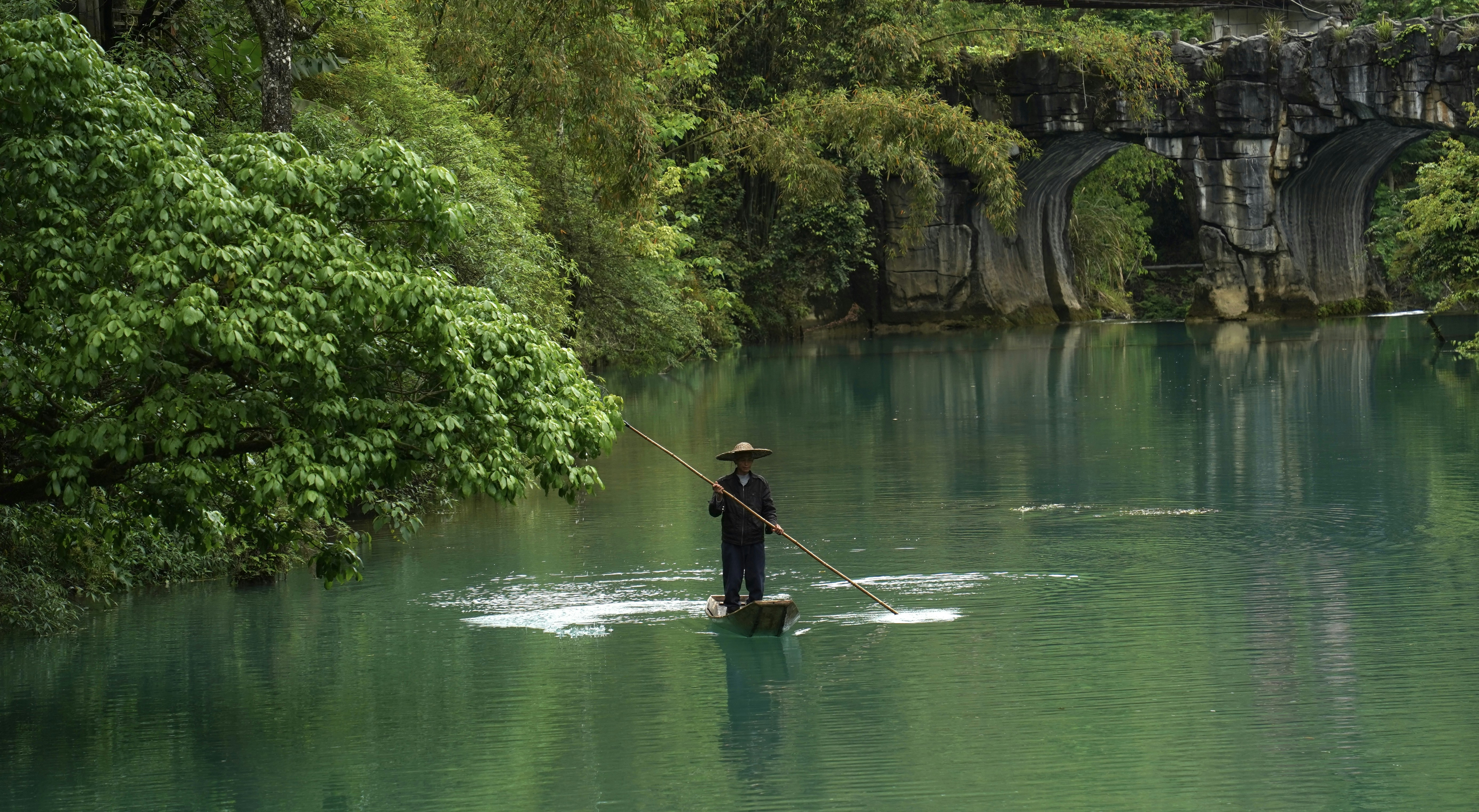 Emerald River Solitude: A Boatman Beneath Ancient Arches