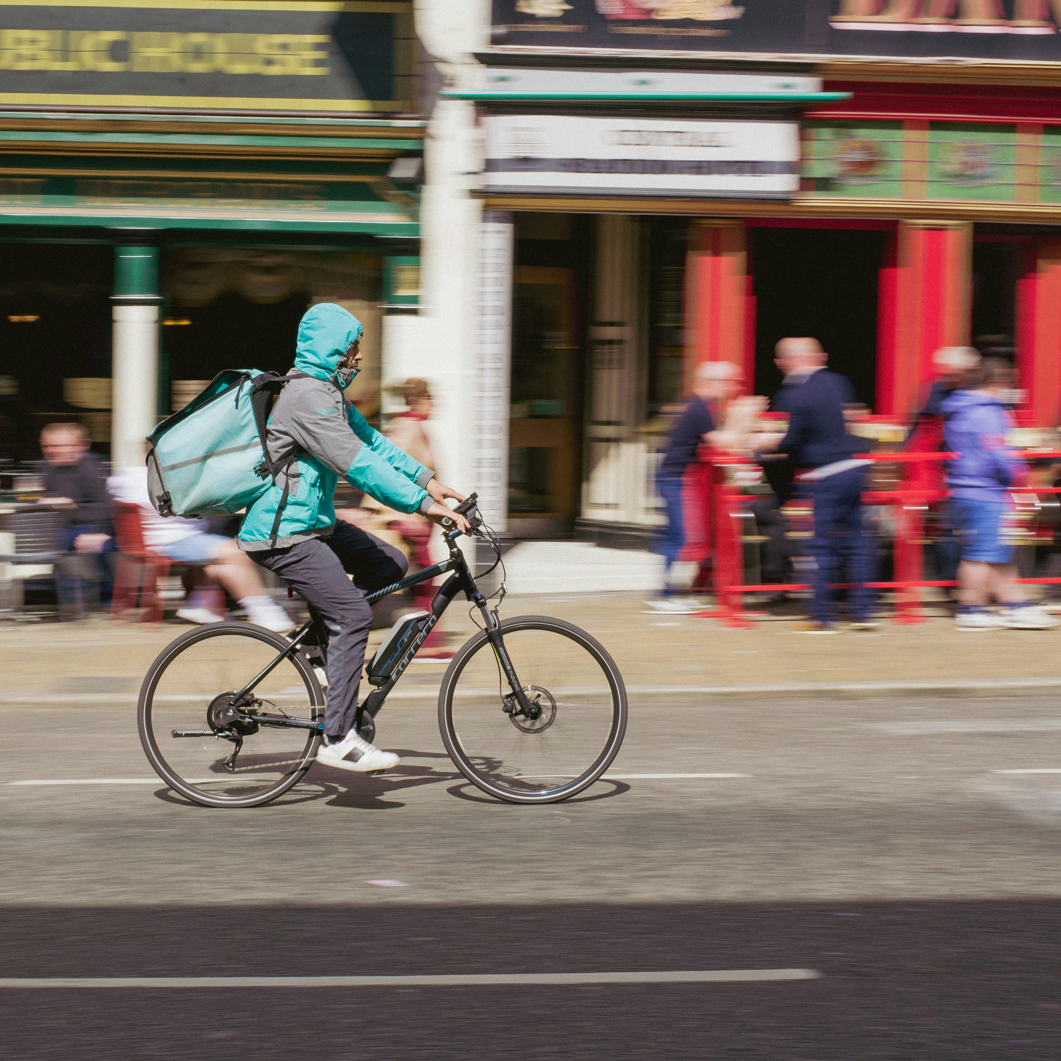 Turquoise-Clad Cyclist Blurs Past City Shopfronts