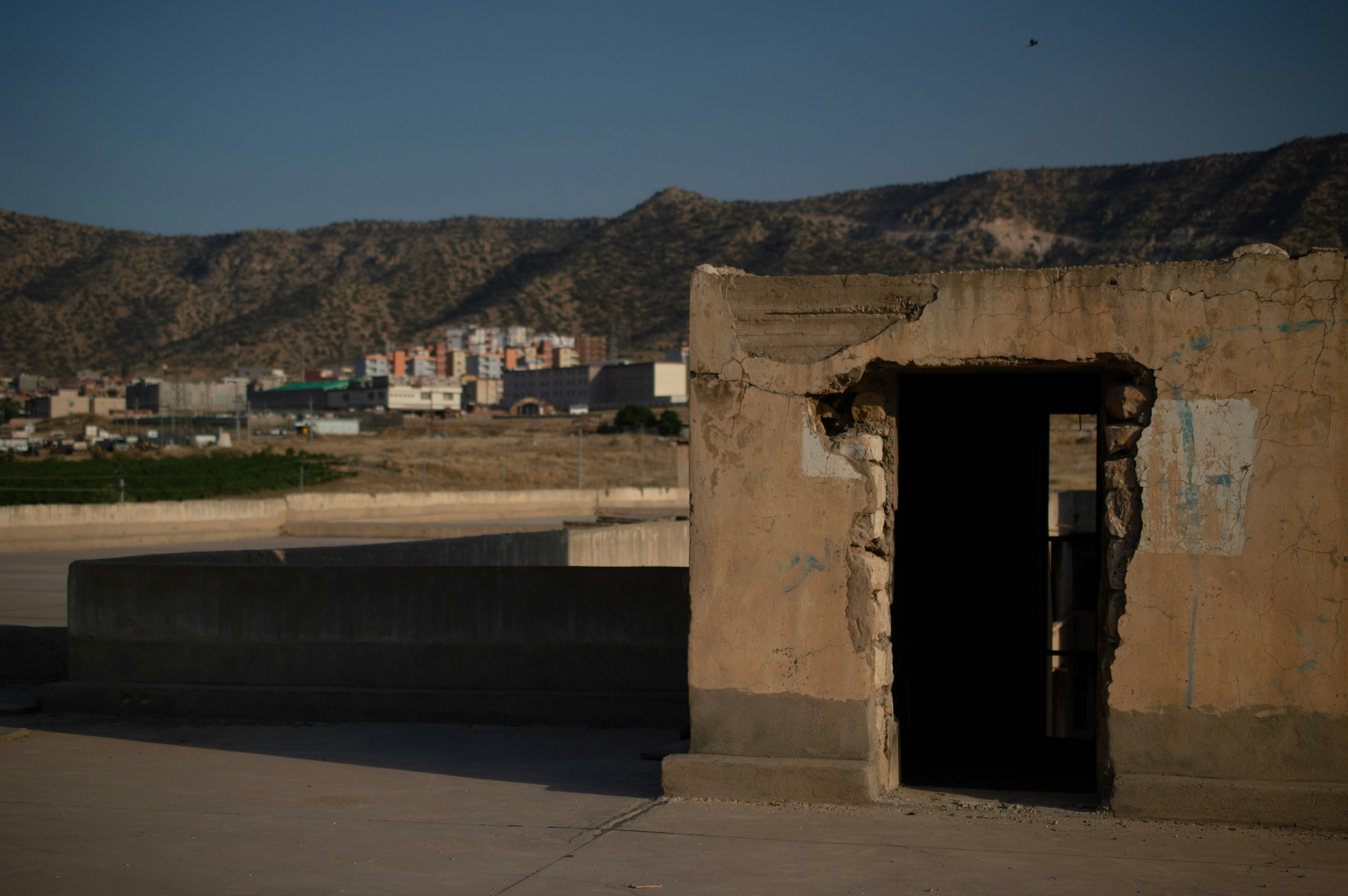 A stone wall with a door and a town in the background photo – Free Iraq ...