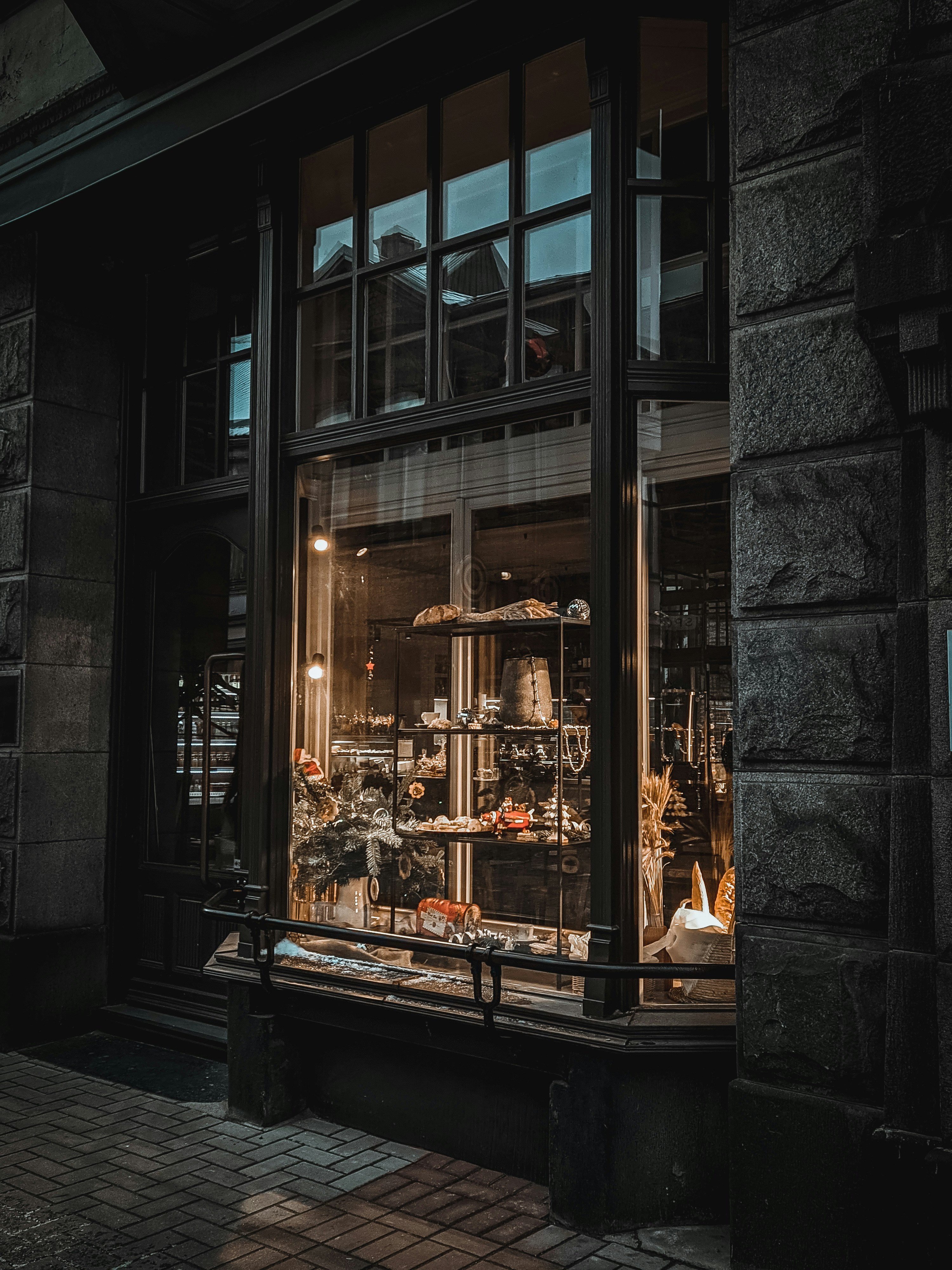 A beautifully arranged display of unique items in a shop window, illuminated by warm lights, showcasing a blend of artistry and craftsmanship.