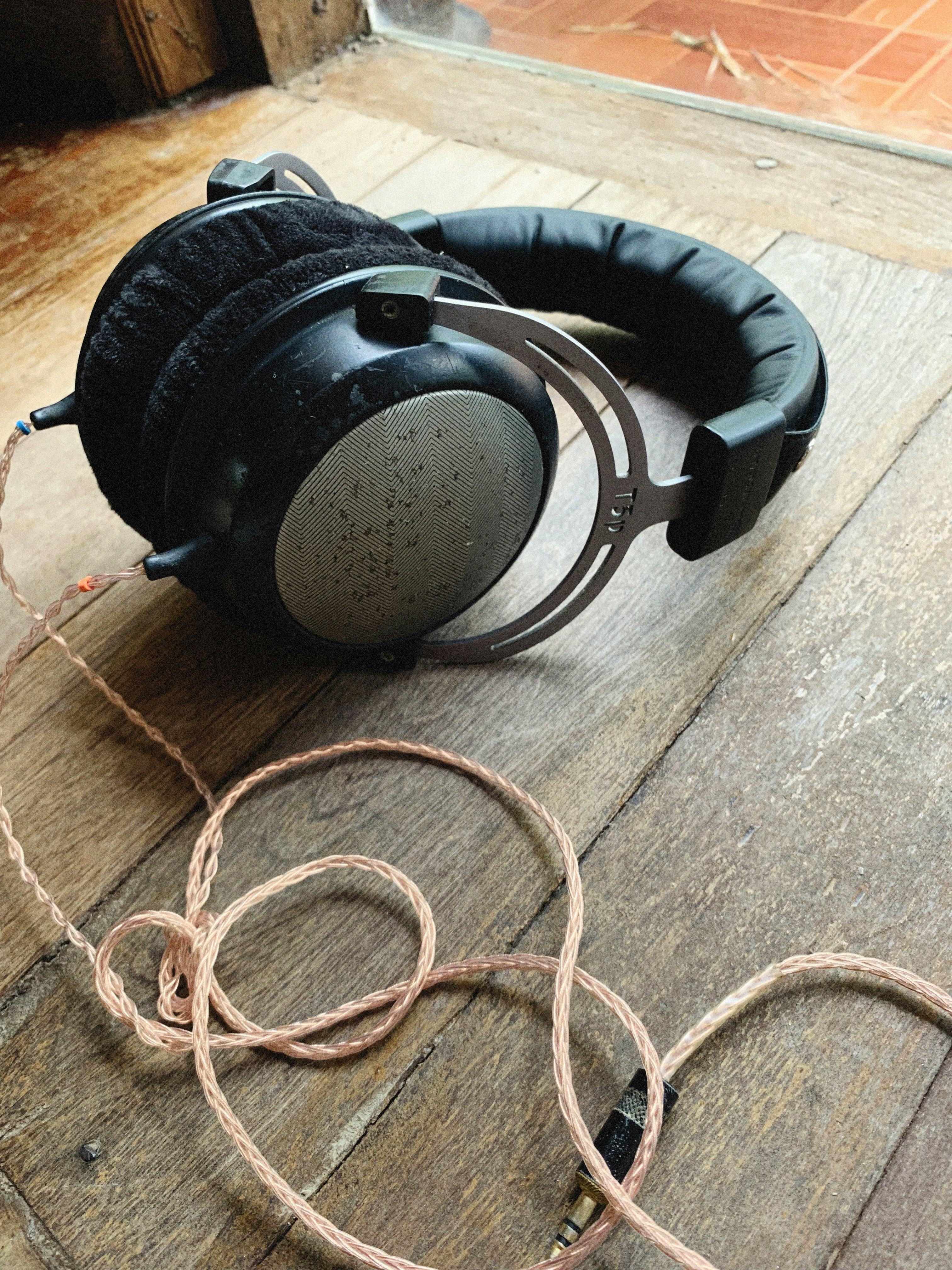 Vintage black headphones resting on a wooden surface, with a tangled cable hinting at stories of music and memories.