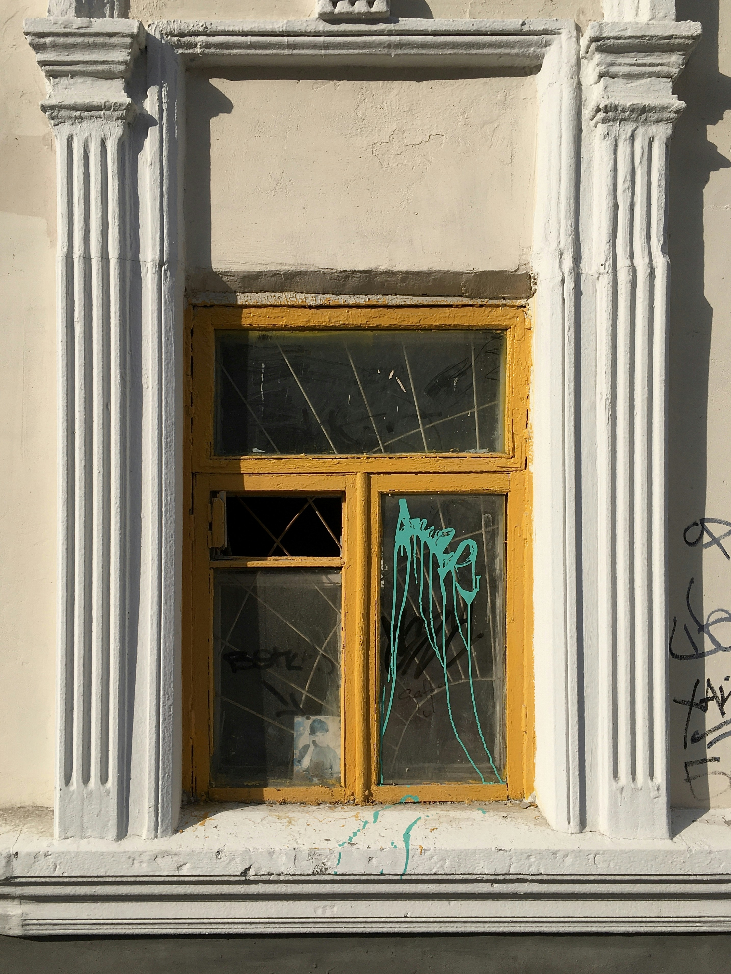 Yellow Window Framed by Neoclassical Columns and Graffiti