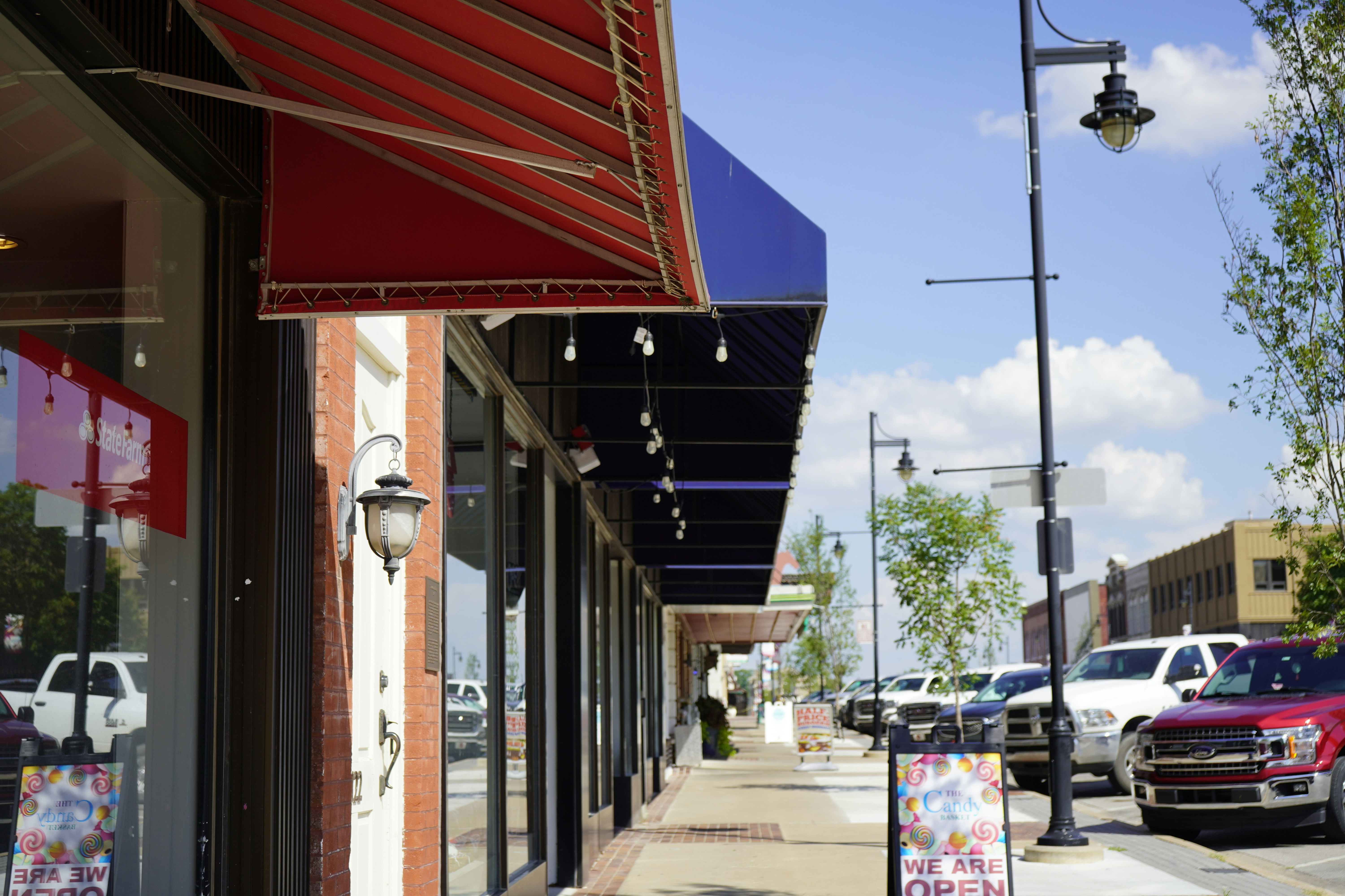 Street scene with colorful awnings and parked vehicles under a clear sky.