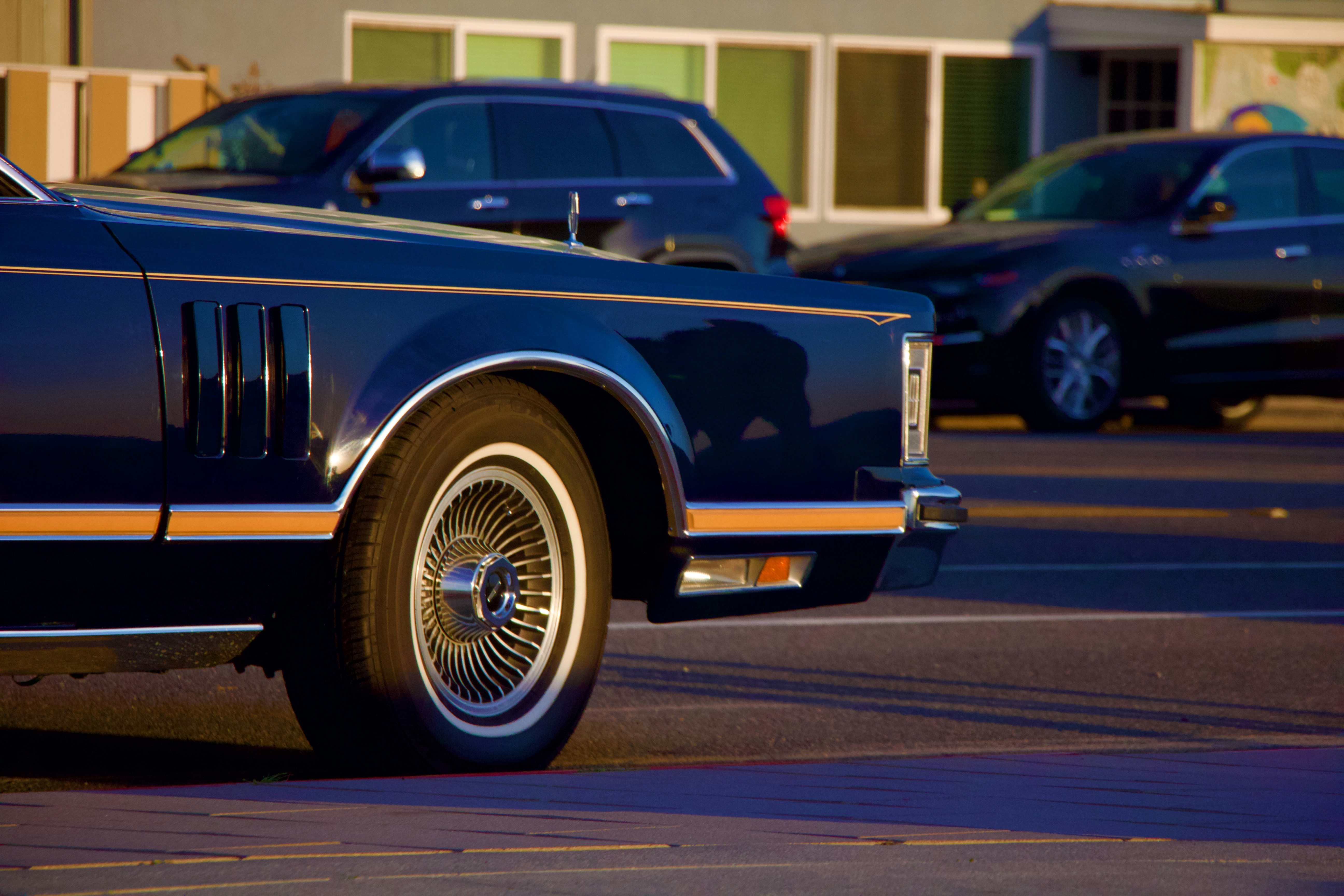 Evening Glint on a Vintage Chrome Wheel in a Quiet Parking Lot