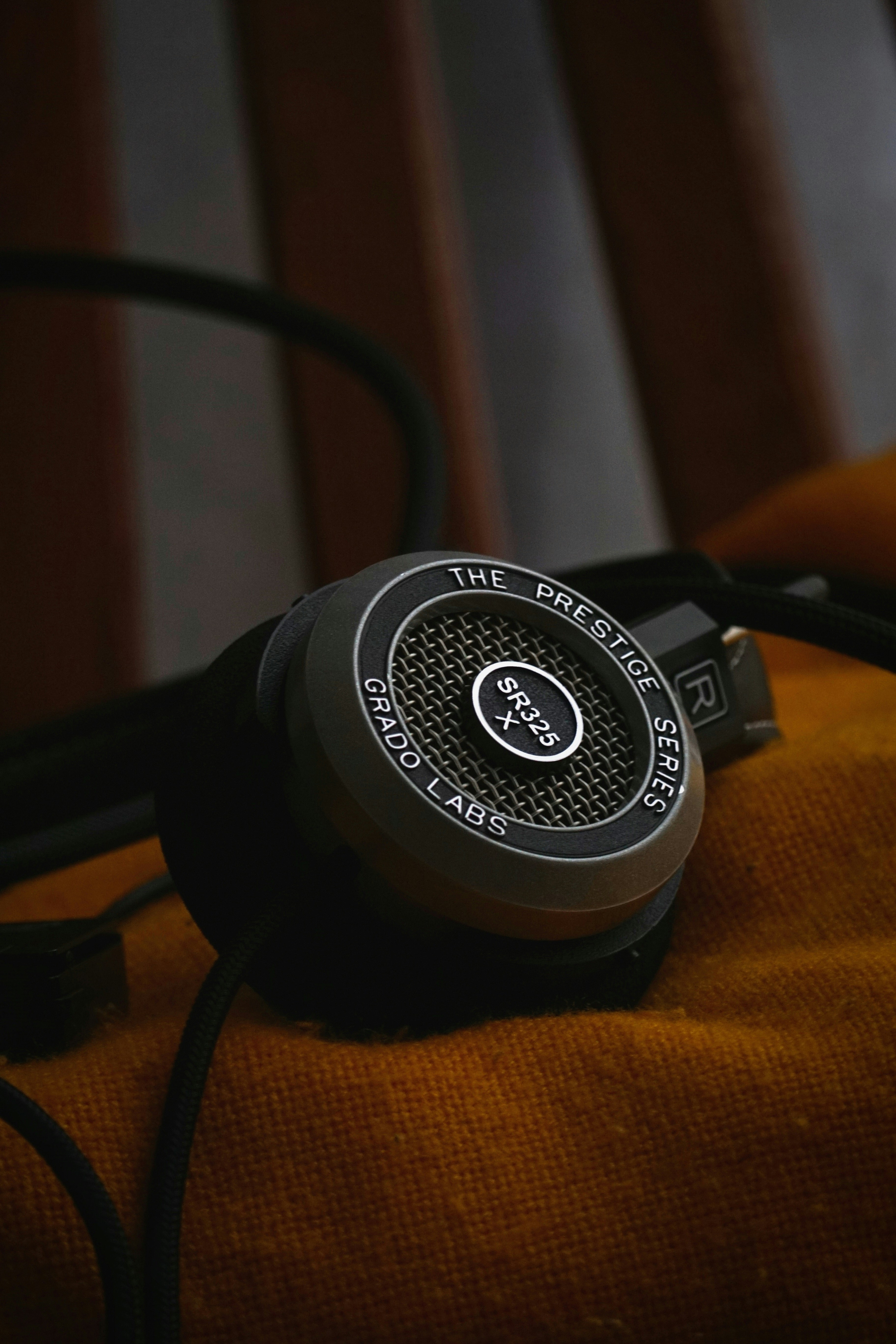 Grado Labs SR325x headphones resting on a textured orange surface, showcasing their intricate design and craftsmanship.